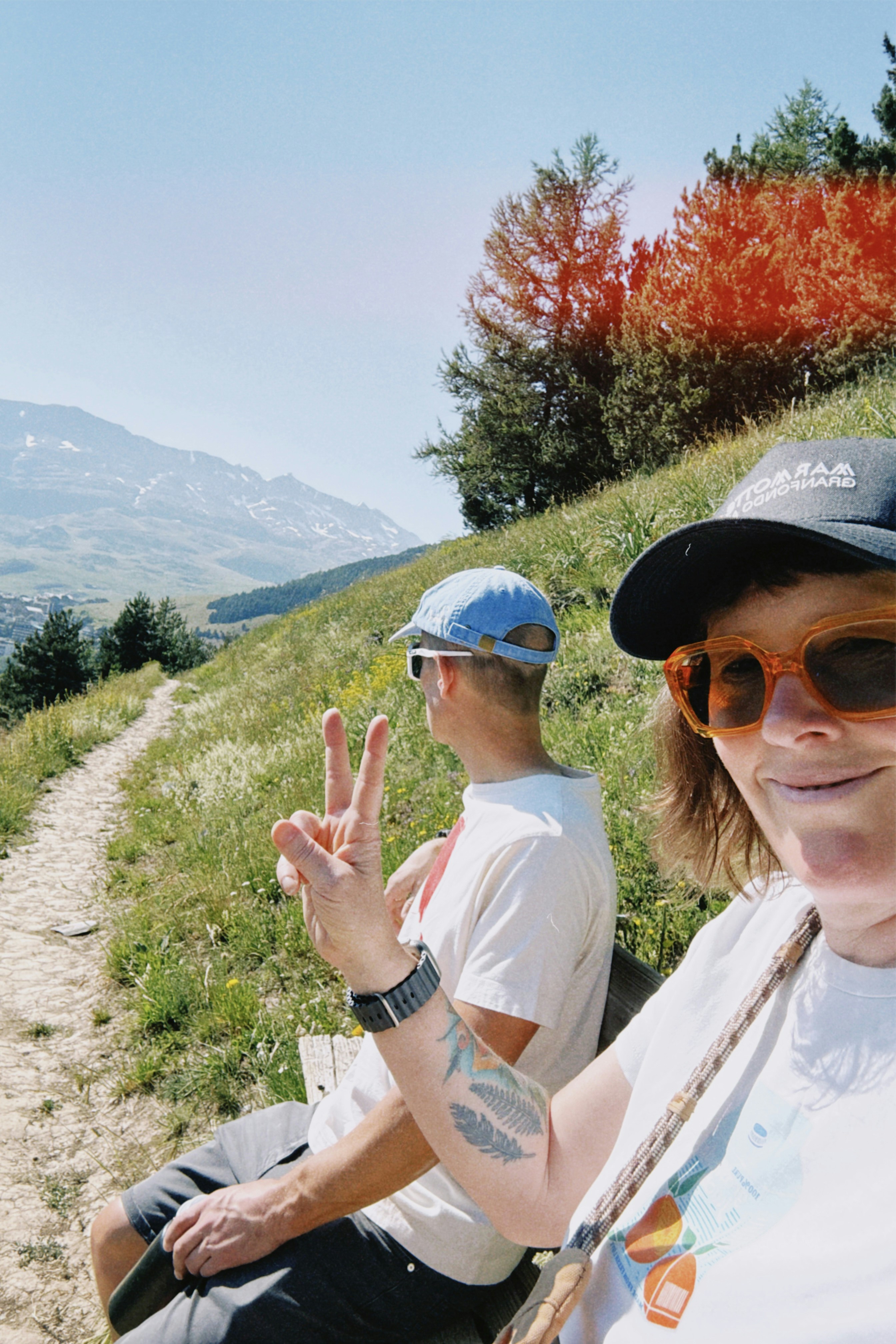 Sunlit hillside selfie with a peace sign and a scenic path