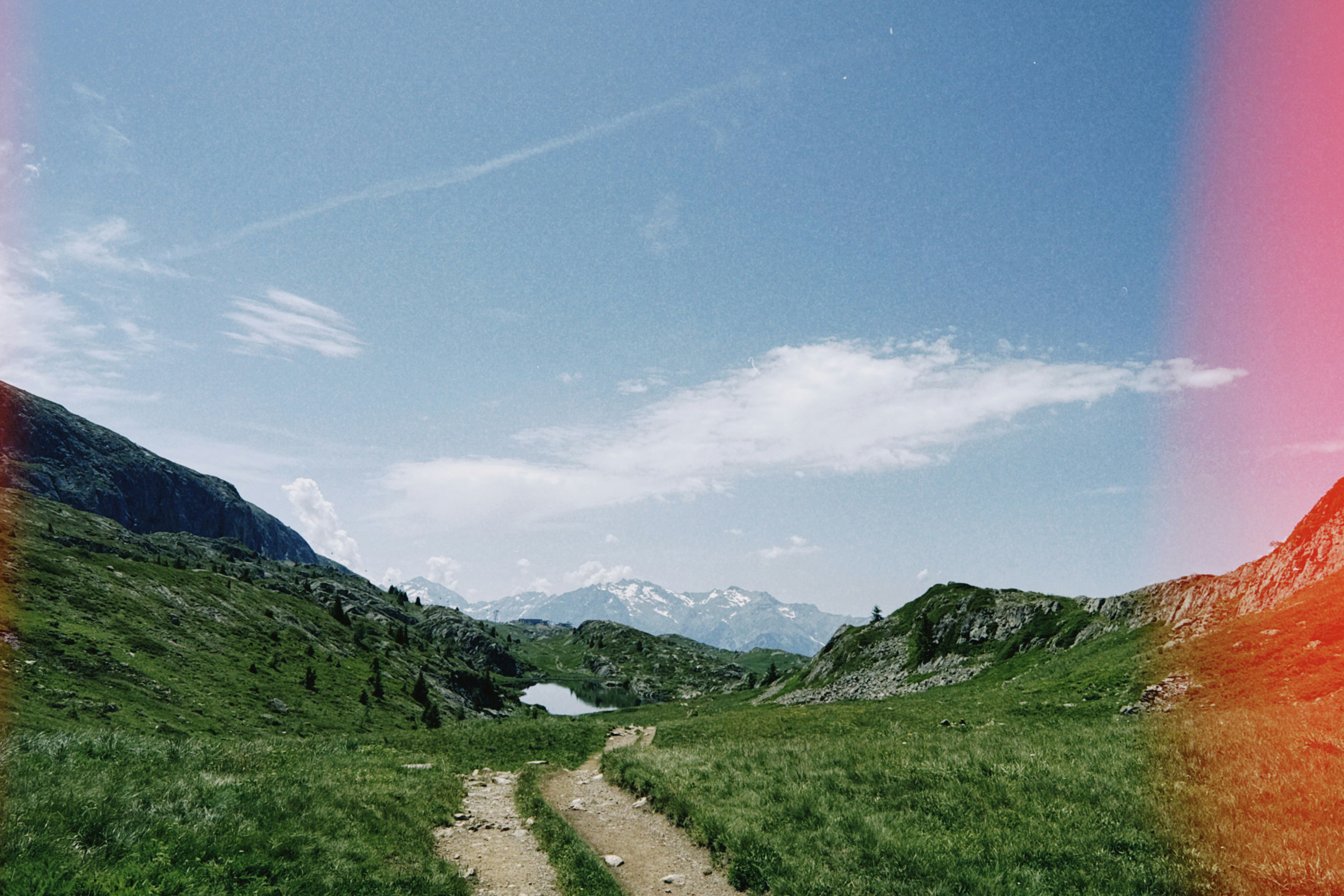 Trail Through Alpine Green: Pathway Toward Snow-Capped Peaks