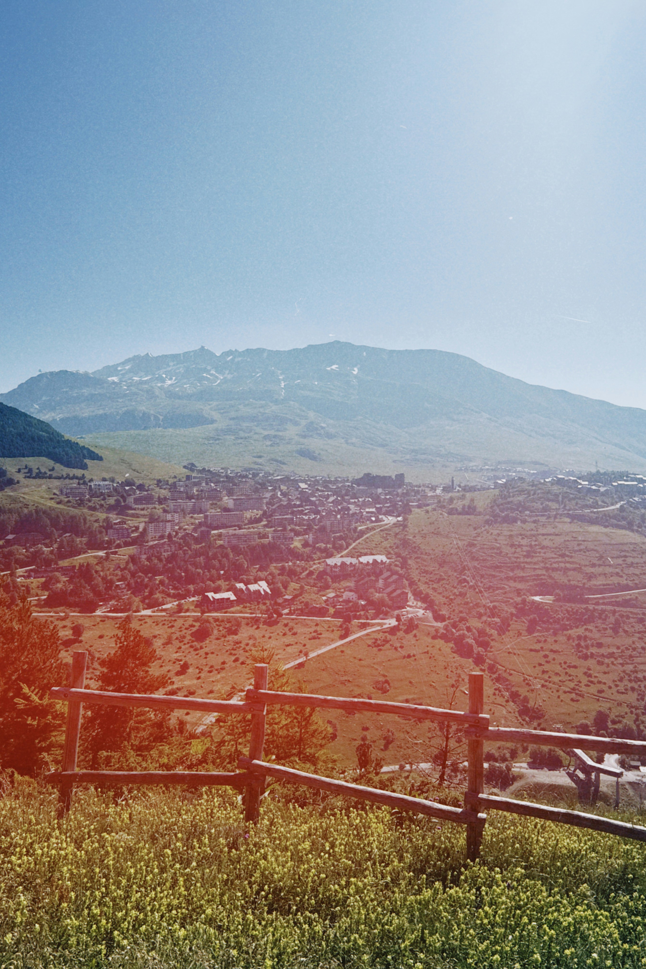 Red-tinged valley over a wooden fence under a clear sky