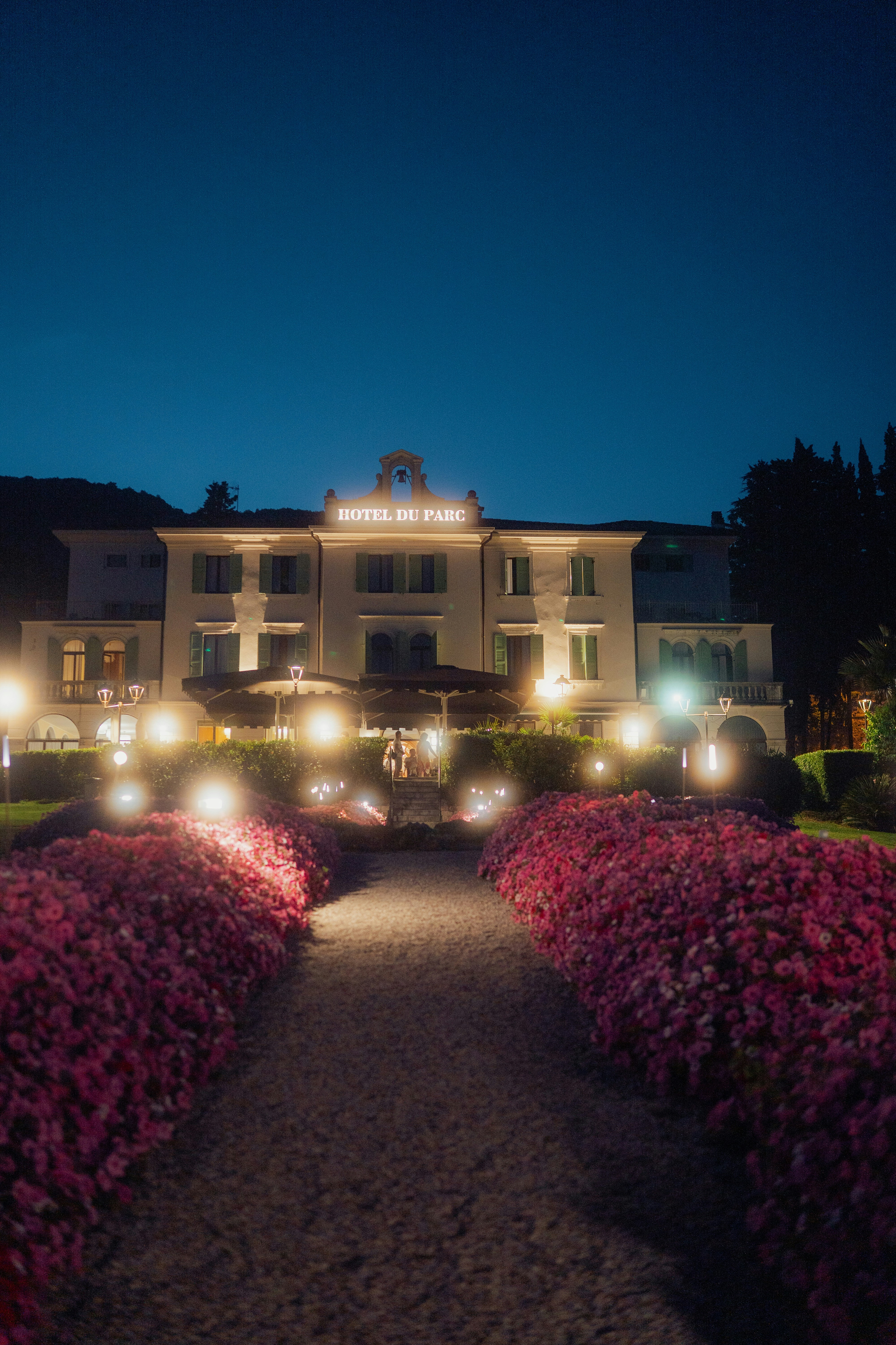 Morning at Hotel du Parc: Lantern-lit Path to a Crescent of Blooms