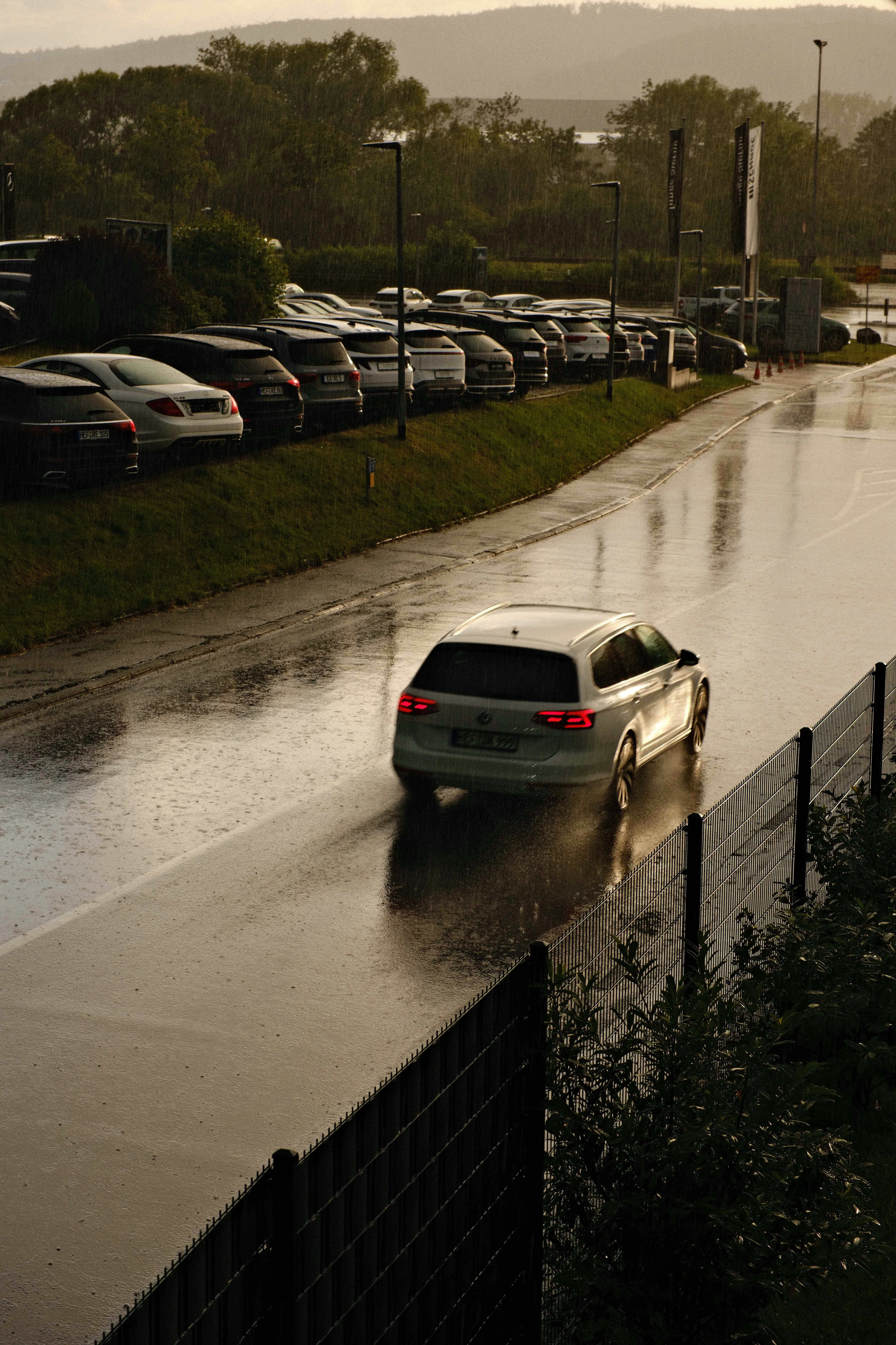 Shafted by Rain: A Silver Car Navigates a Shiny Street