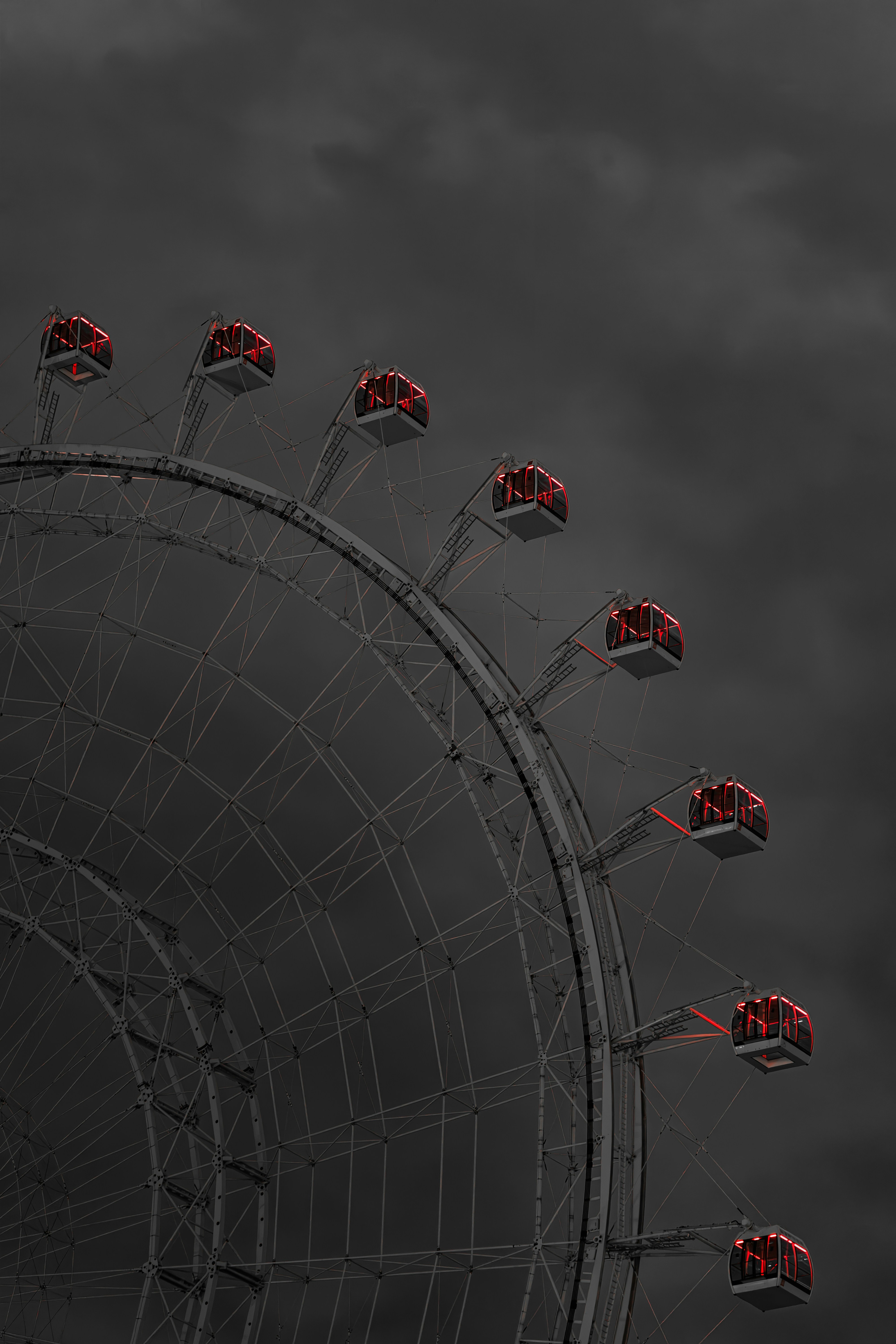 Red cabins along a colossal wheel: a moody ferris wheel at dusk