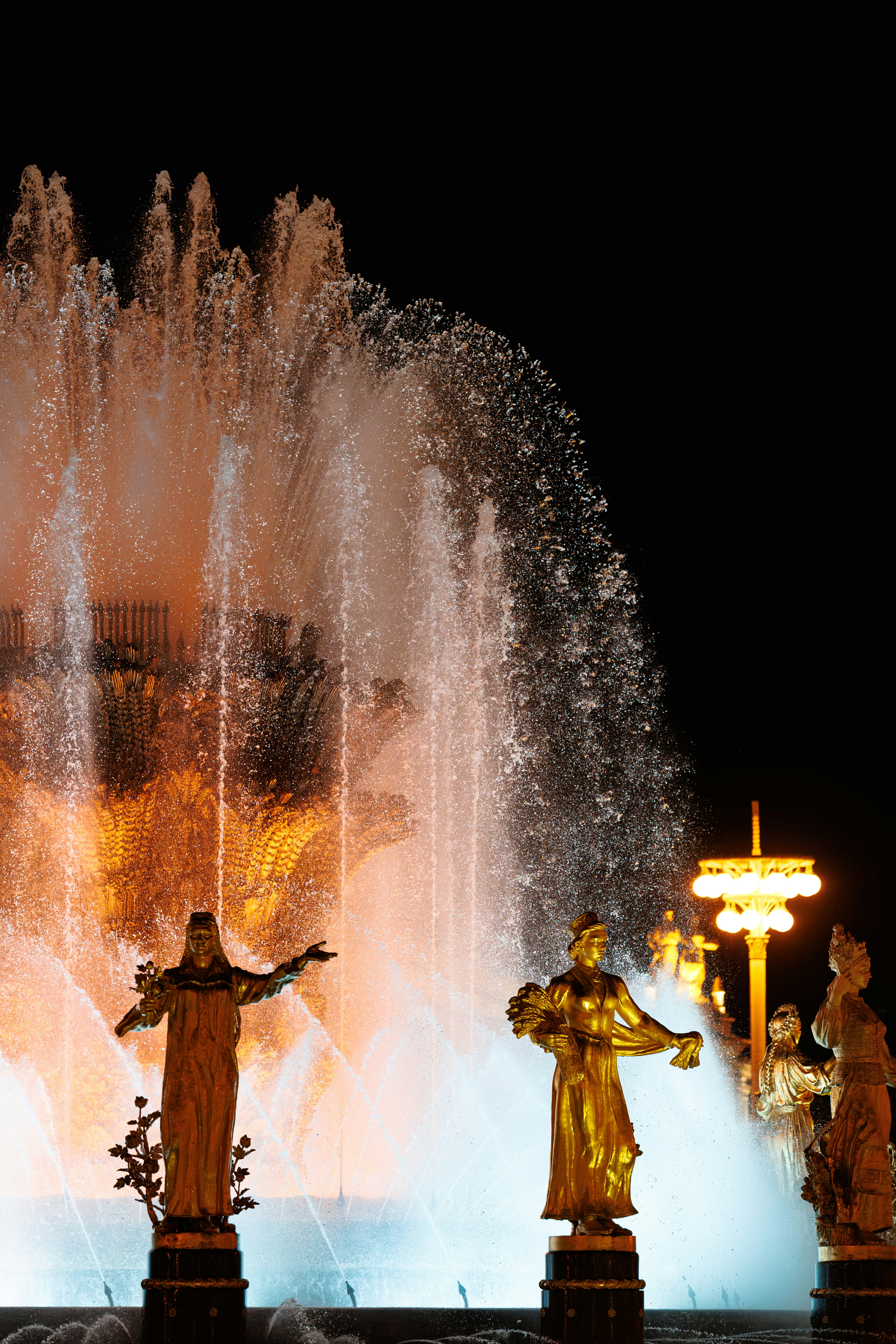 Golden Statues Beneath a Nighttime Fountainscape