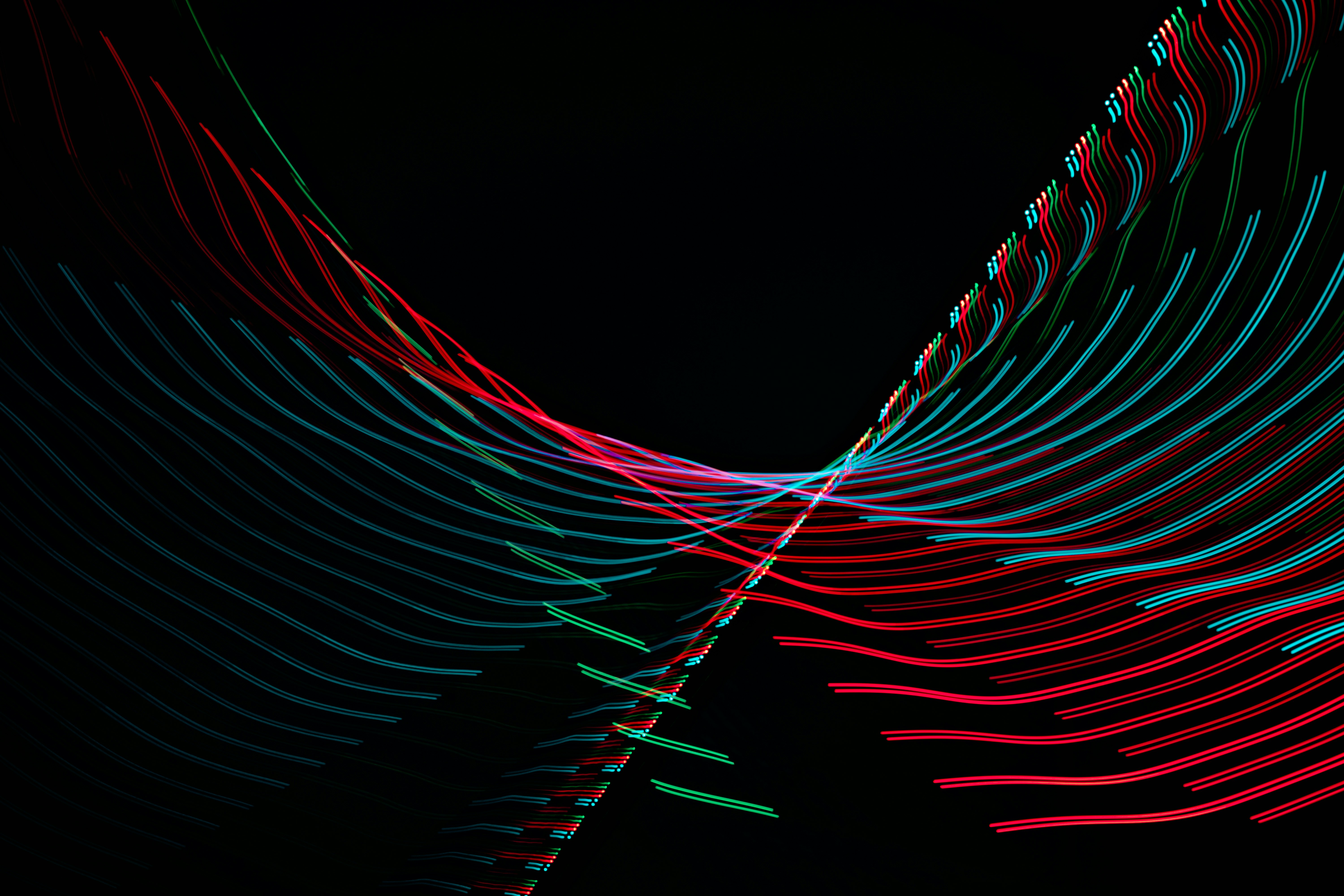 Abstract light trails converge toward a dark center, emphasizing motion and rhythm against a black backdrop. The image features vibrant neon lines that sweep from edges toward a central intersection, highlighting dynamic paths of light.