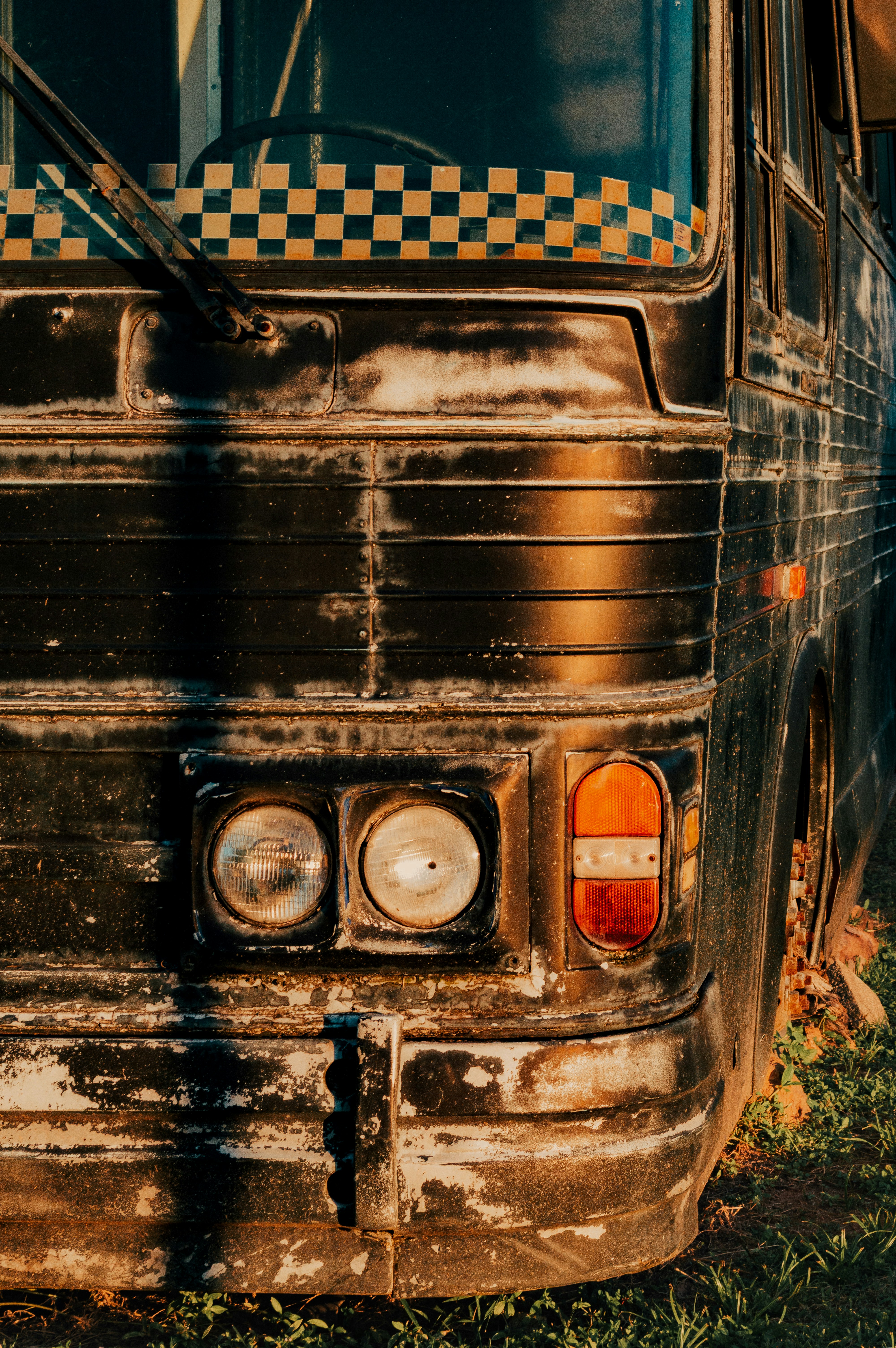 Dusty Front Half of a Bus: Weathered Metal and Checker Patterned Windshield
