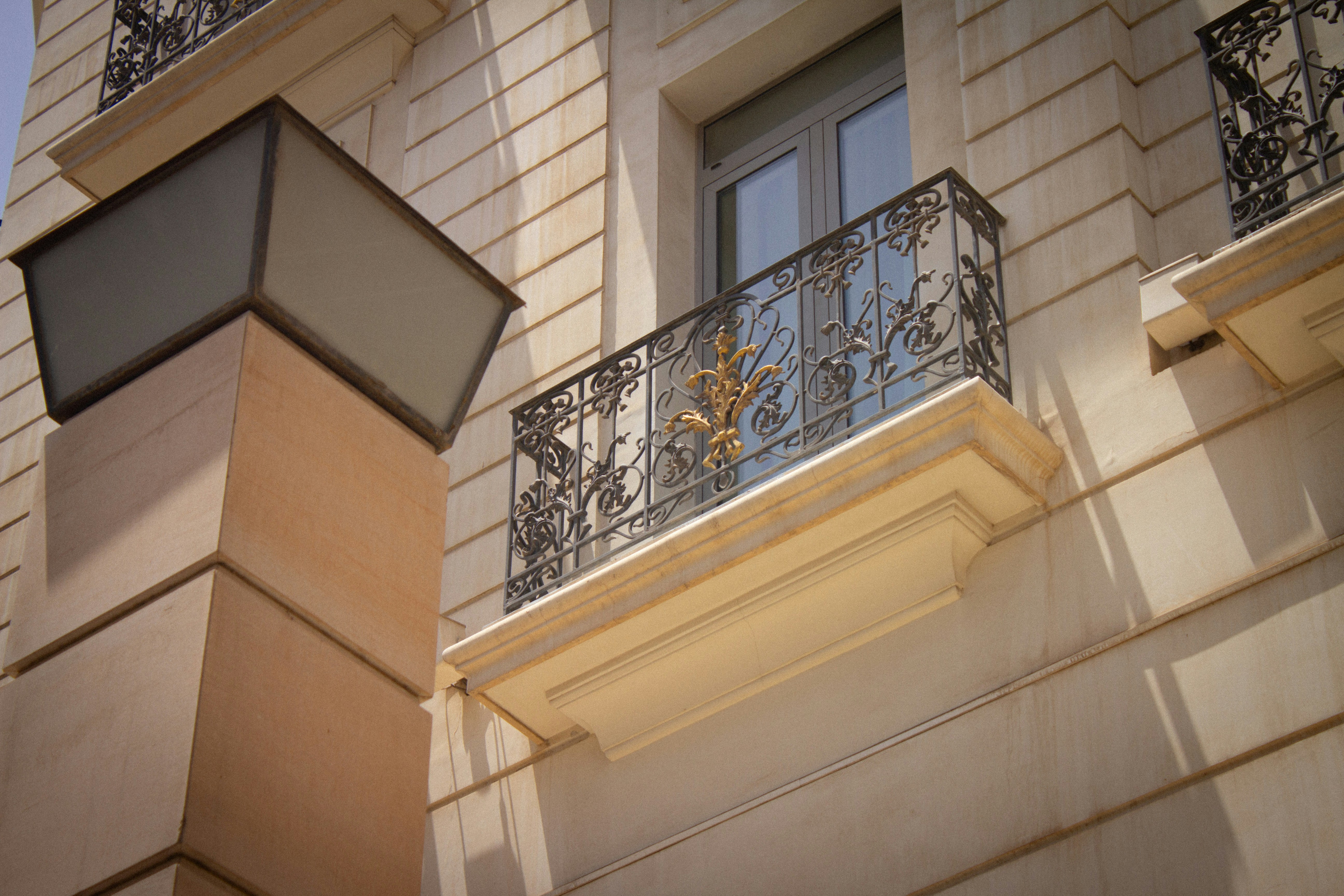 Sunlit Facade and Ornate Balcony on a Parisian-Style Corner