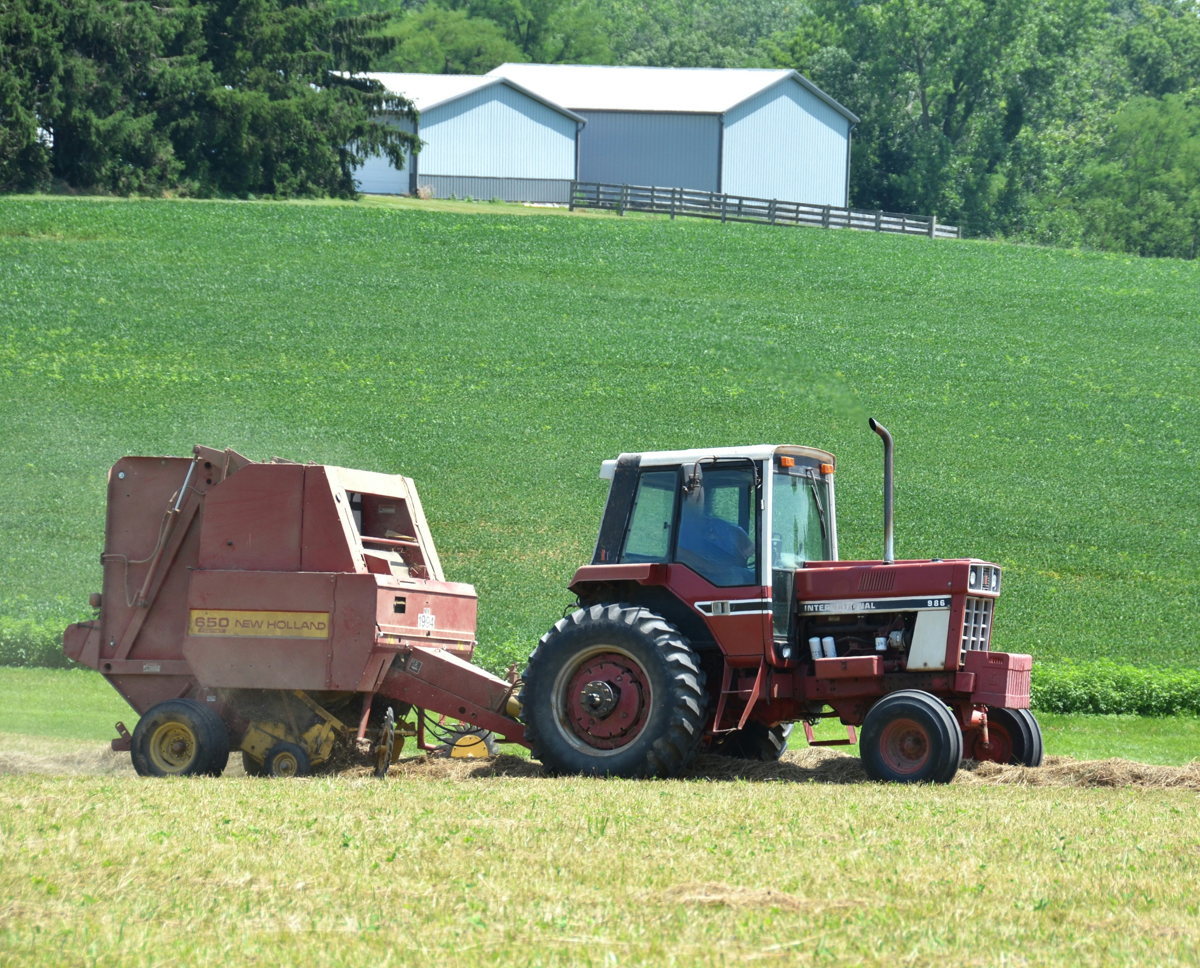 Red Tractor and Balancing Hay Wagon Under Wide Barn Sky