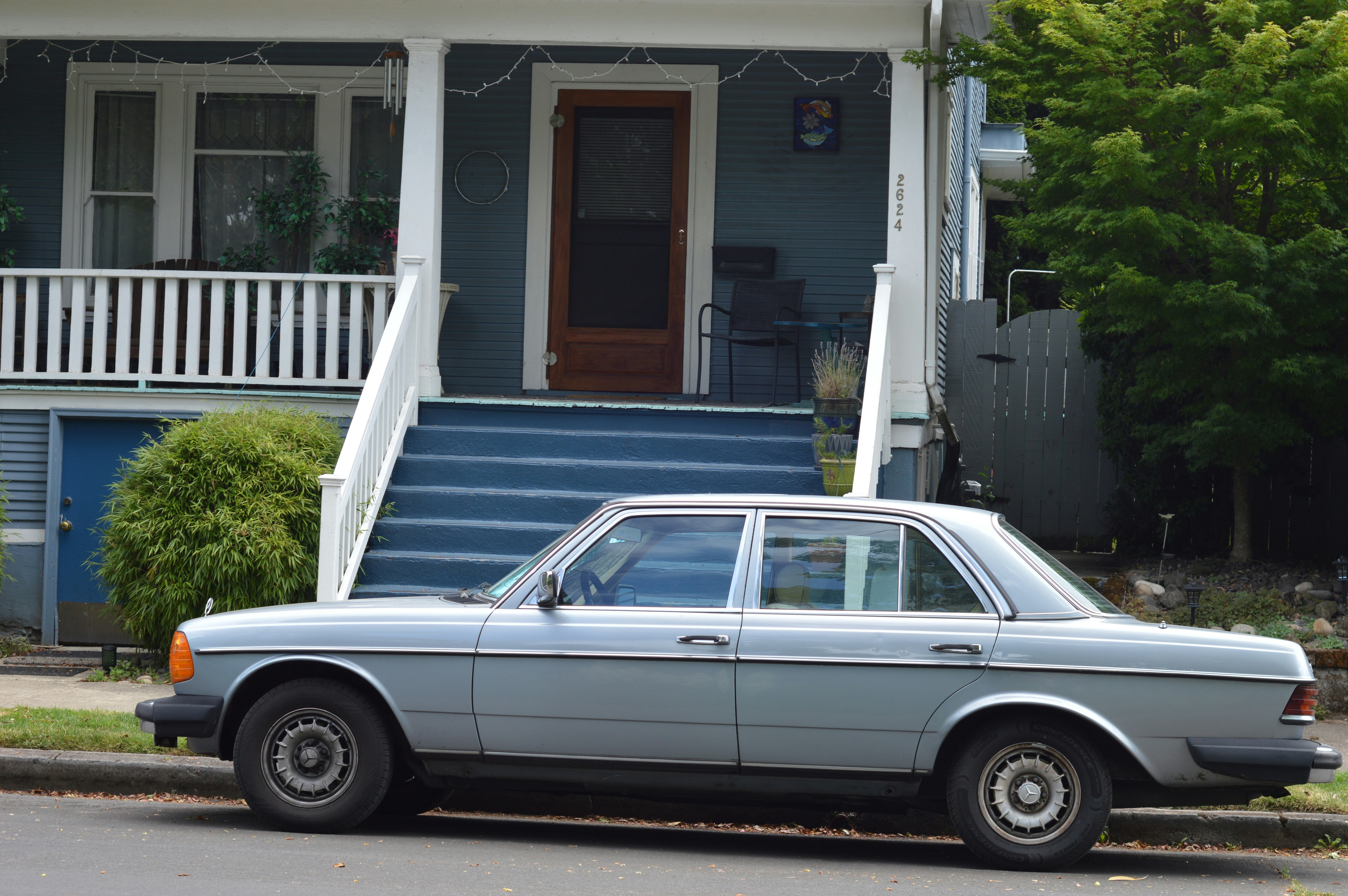 Blue vintage sedan under a porch nestled along a quiet street