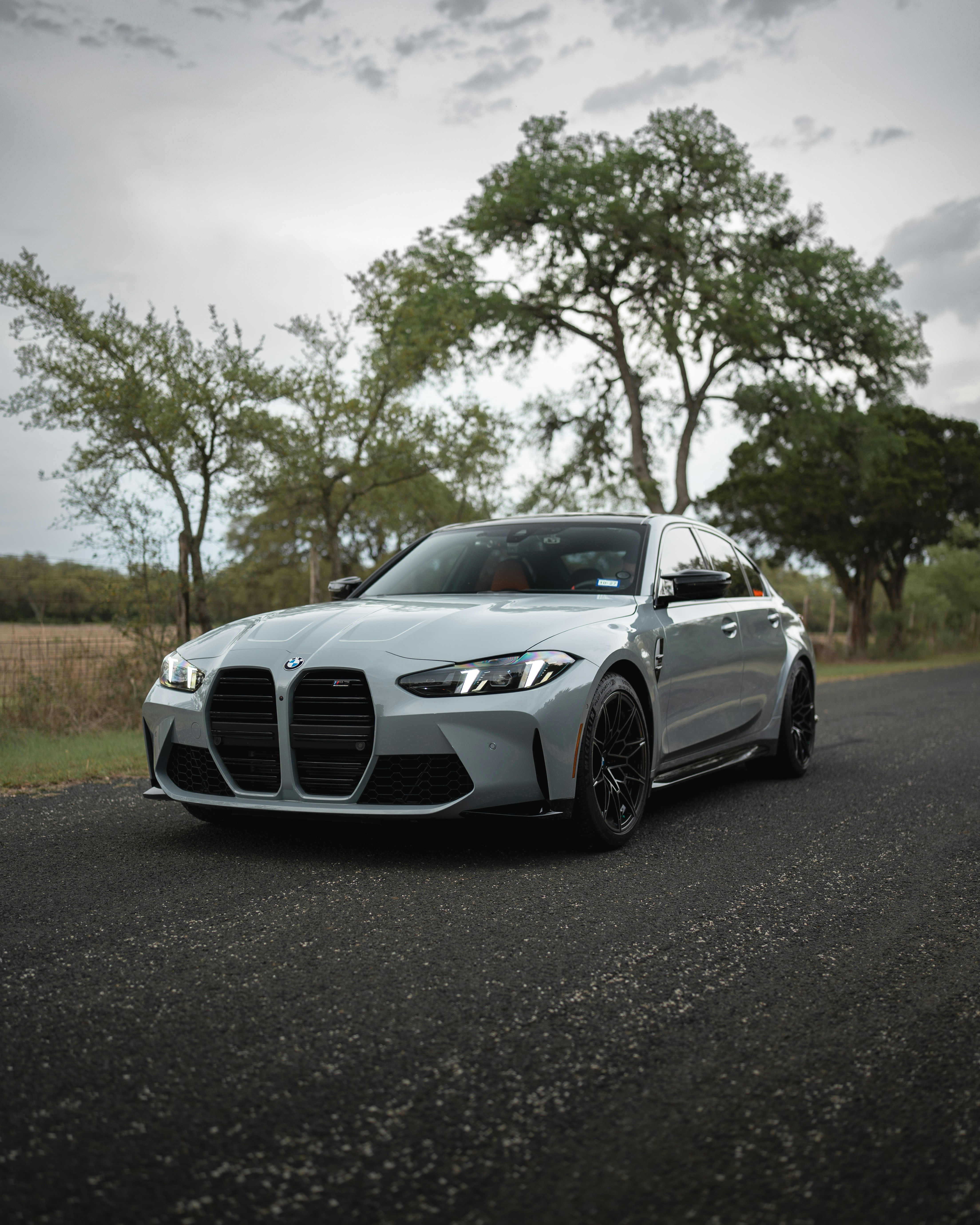 Silver BMW M8-inspired sedan on a rural road