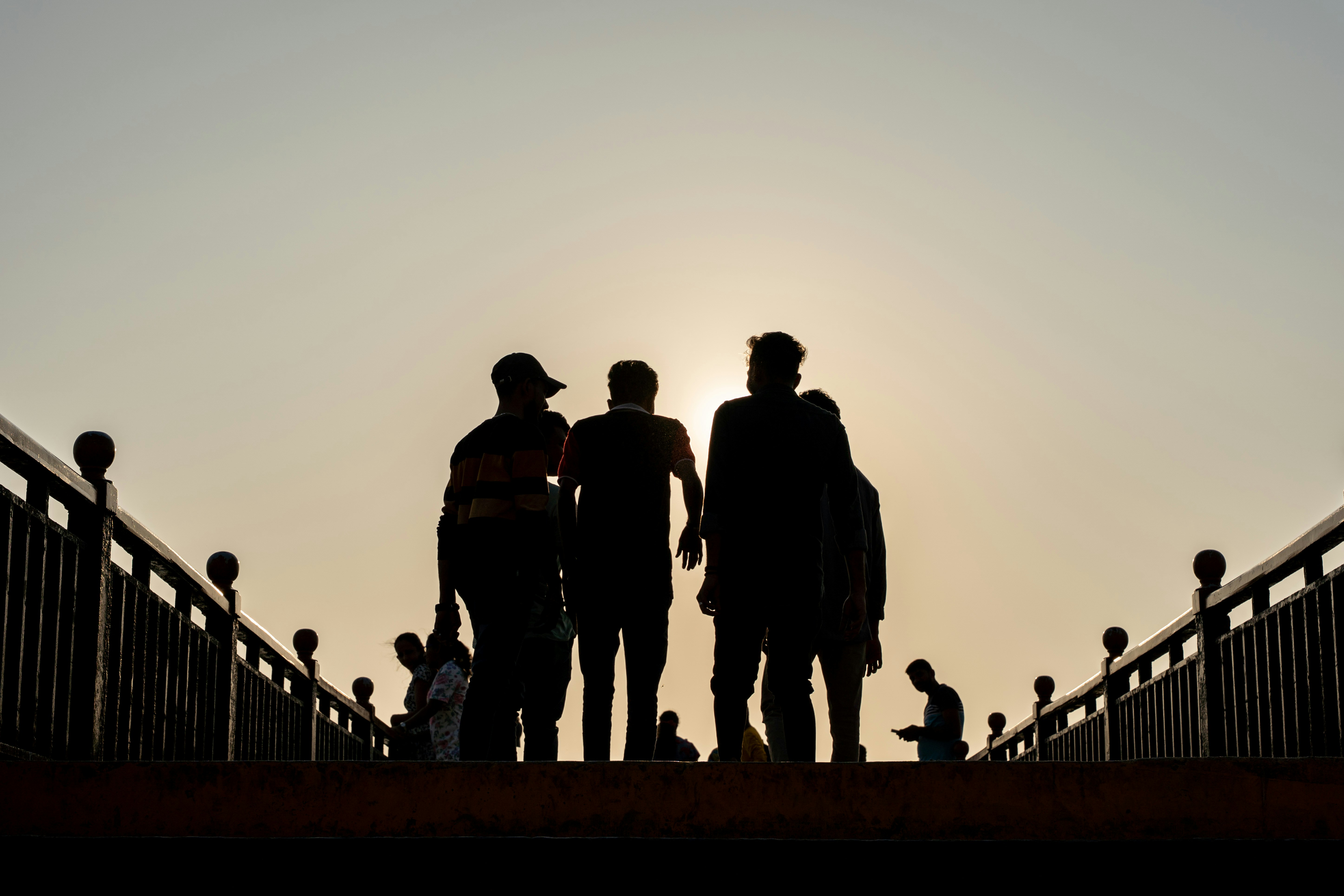 People silhouetted on a bridge during sunset.