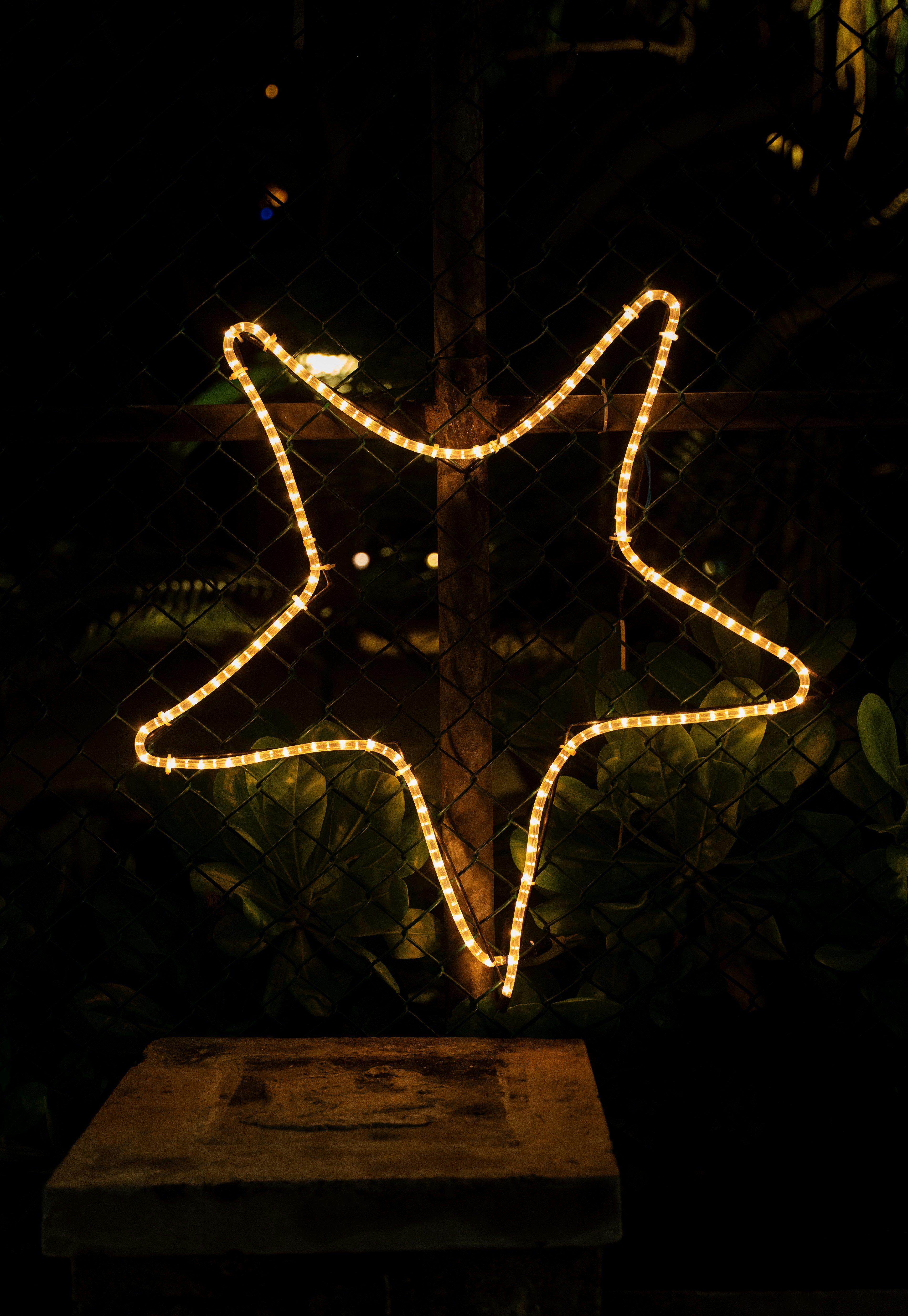 Glowing Star Emblem Draped Over a Fence at Night
