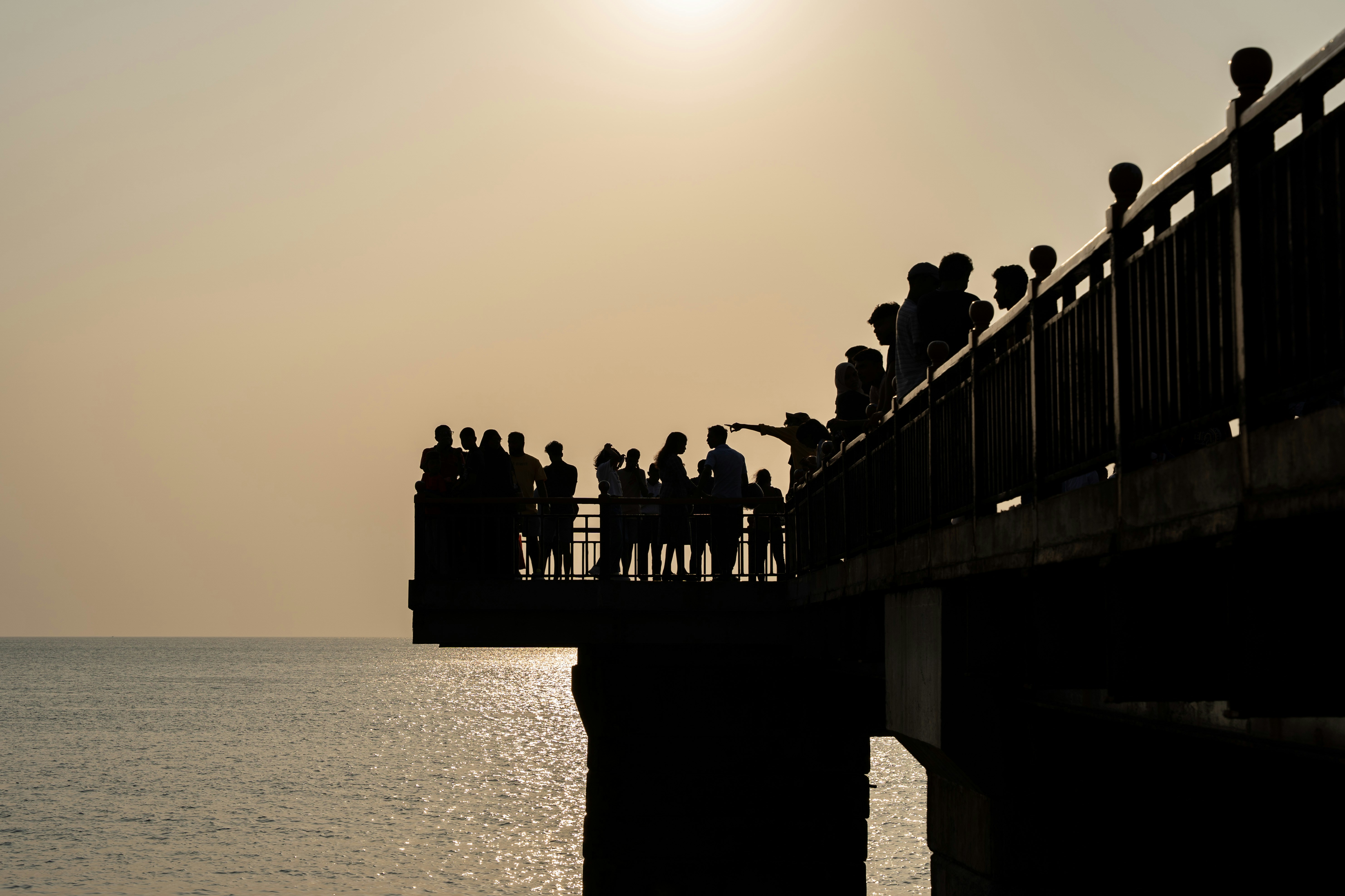 Silhouette at Sunset: People Gather on a Pier Over calm waters