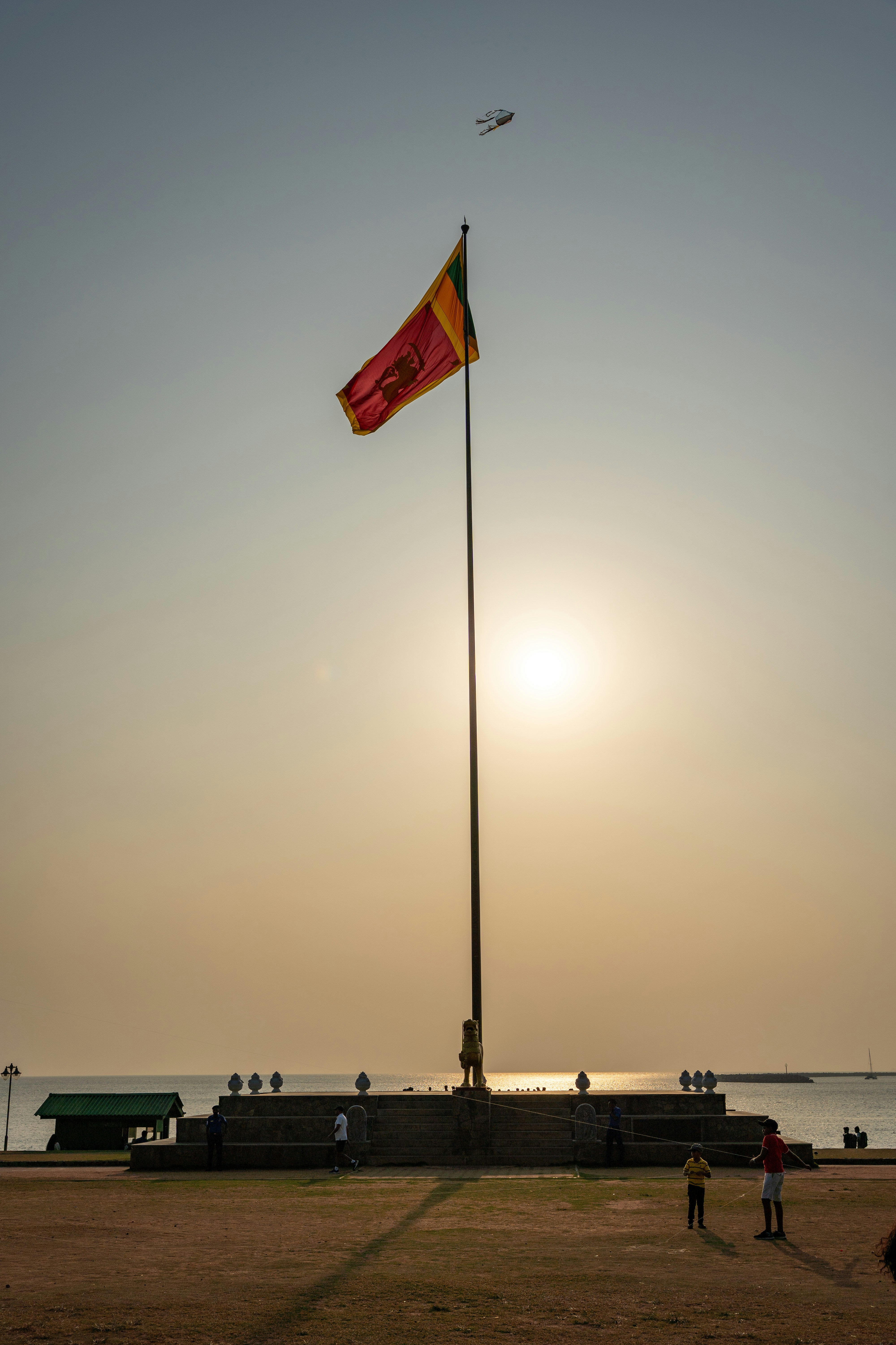 Flagpole at Dusk: A Lone Flag Against a Sunlit Sea