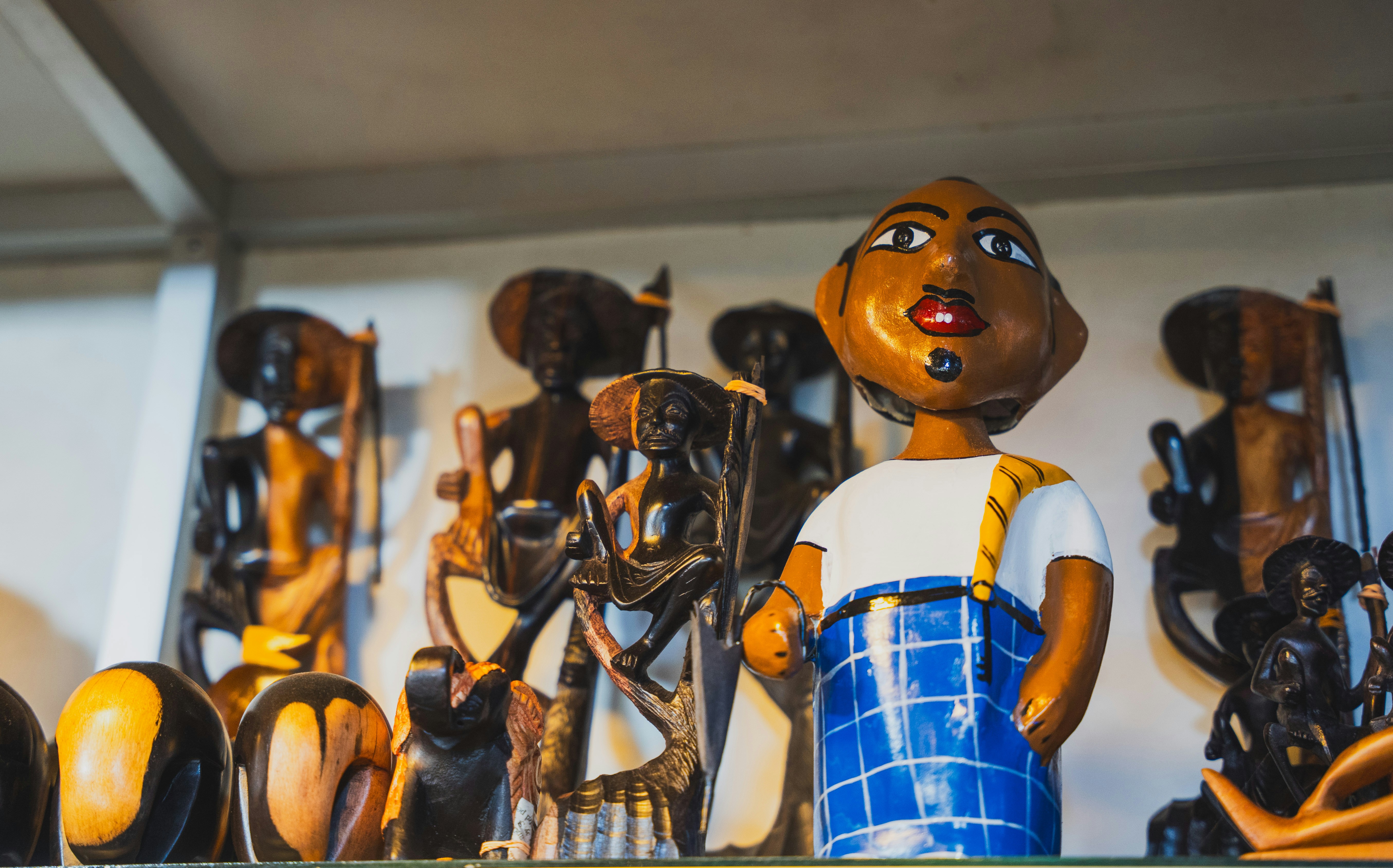 Clay Figurine in a Shelf of Wooden Sculptures