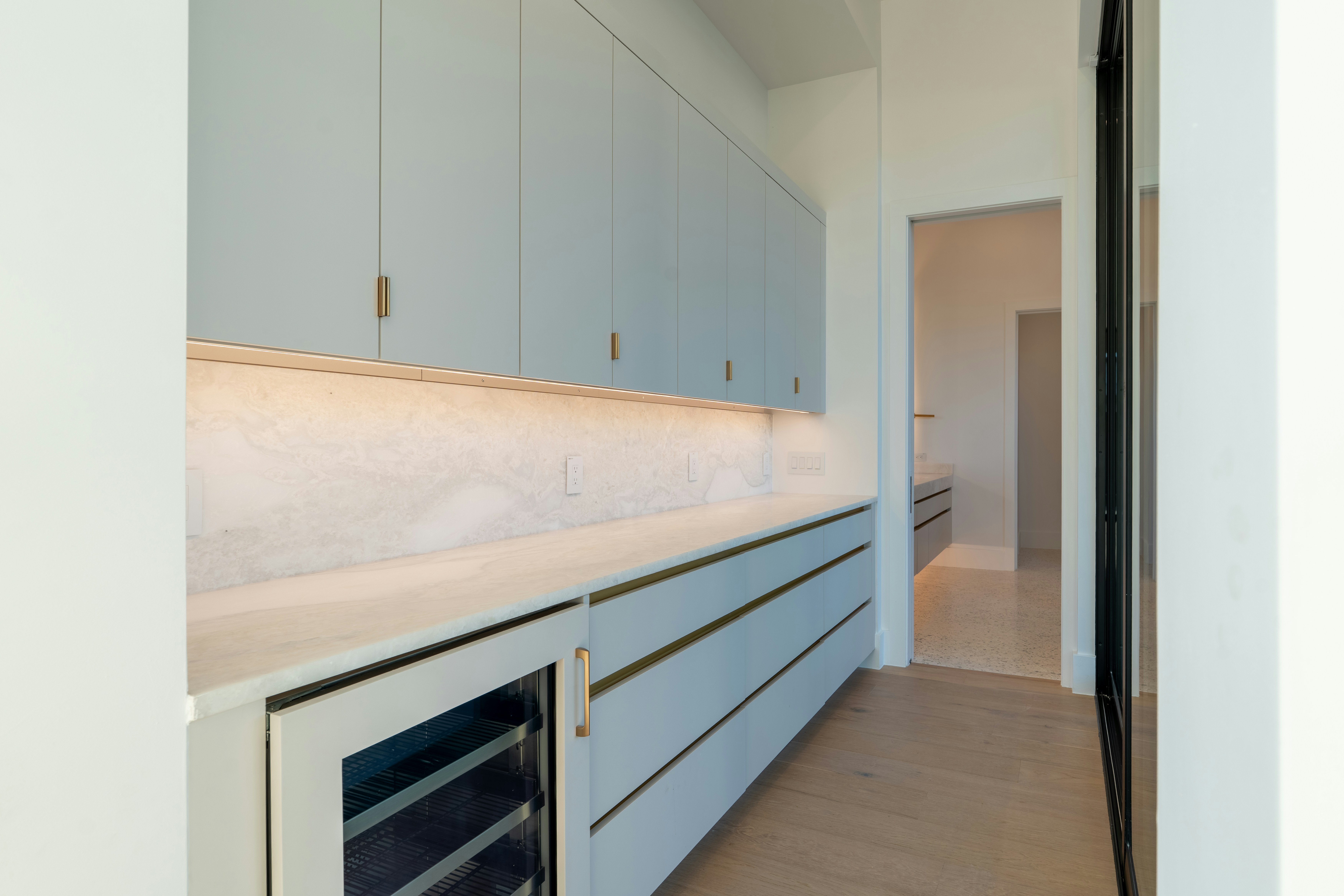 Minimalist Kitchen Corridor with Pale Blue Cabinets and Marble Backsplash