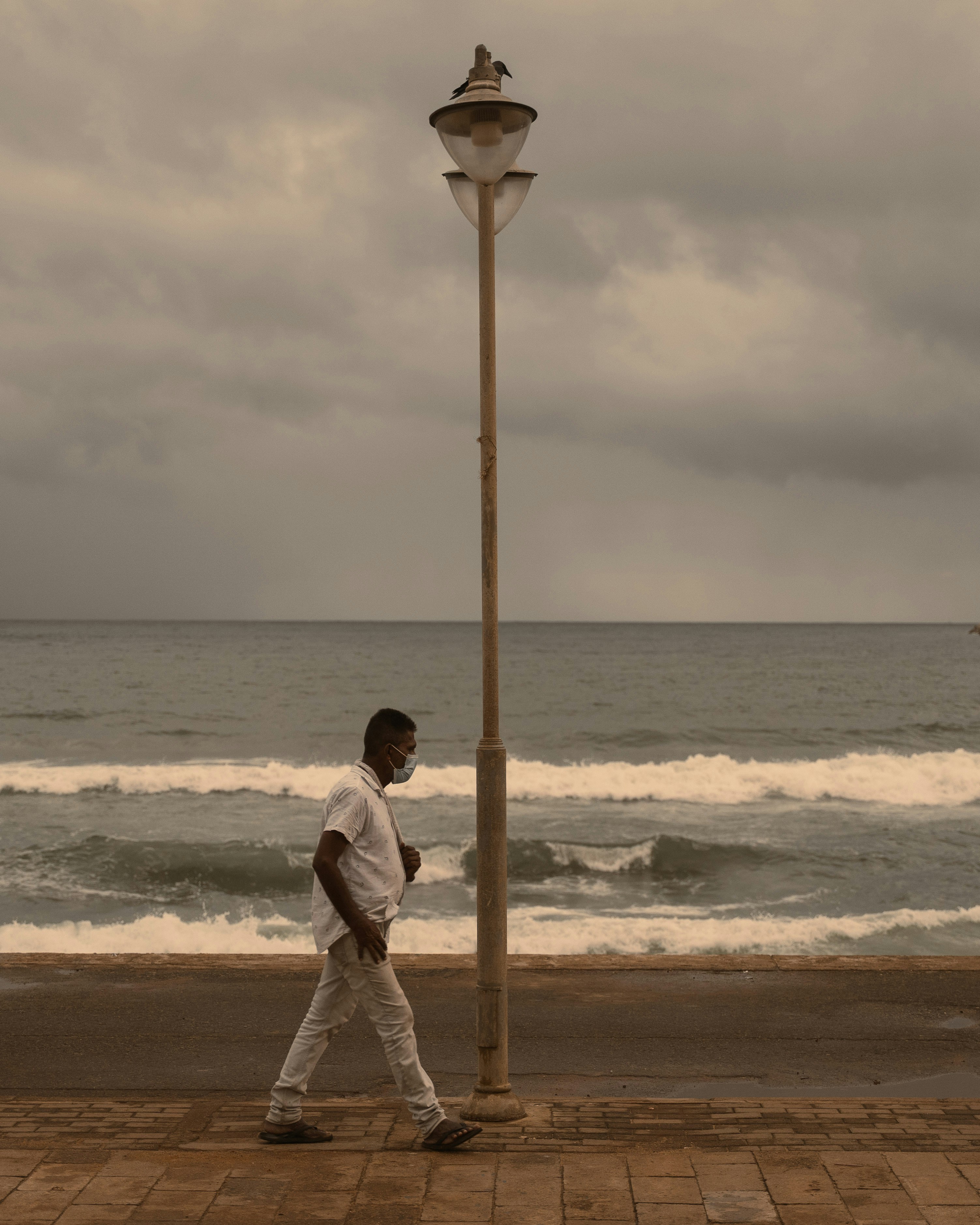 Lone Walker Beneath a Pier-Mast on a Overcast Seafront