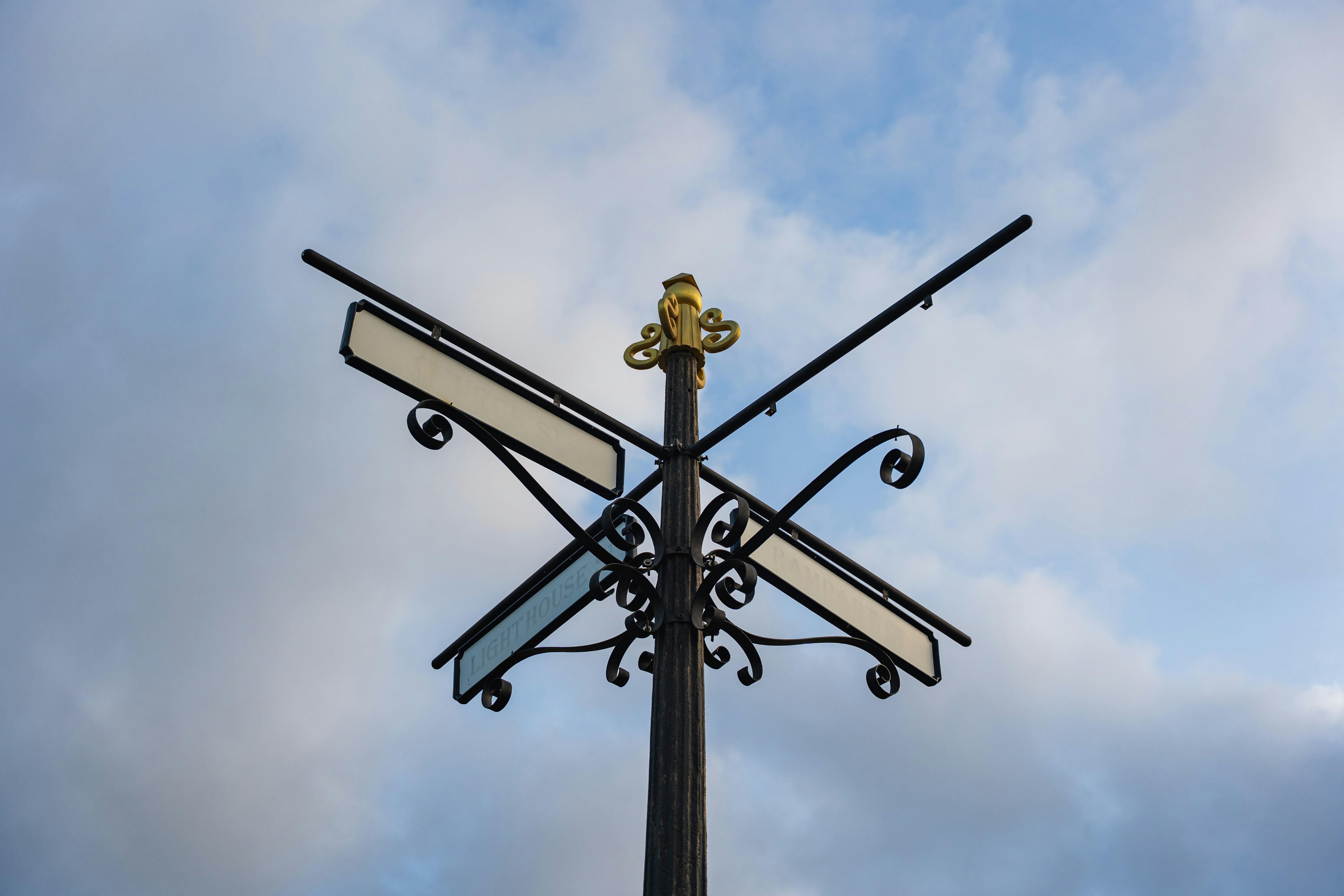 Crossroads of Curved Iron: A Signpost Crowned by Ornate Scrollwork