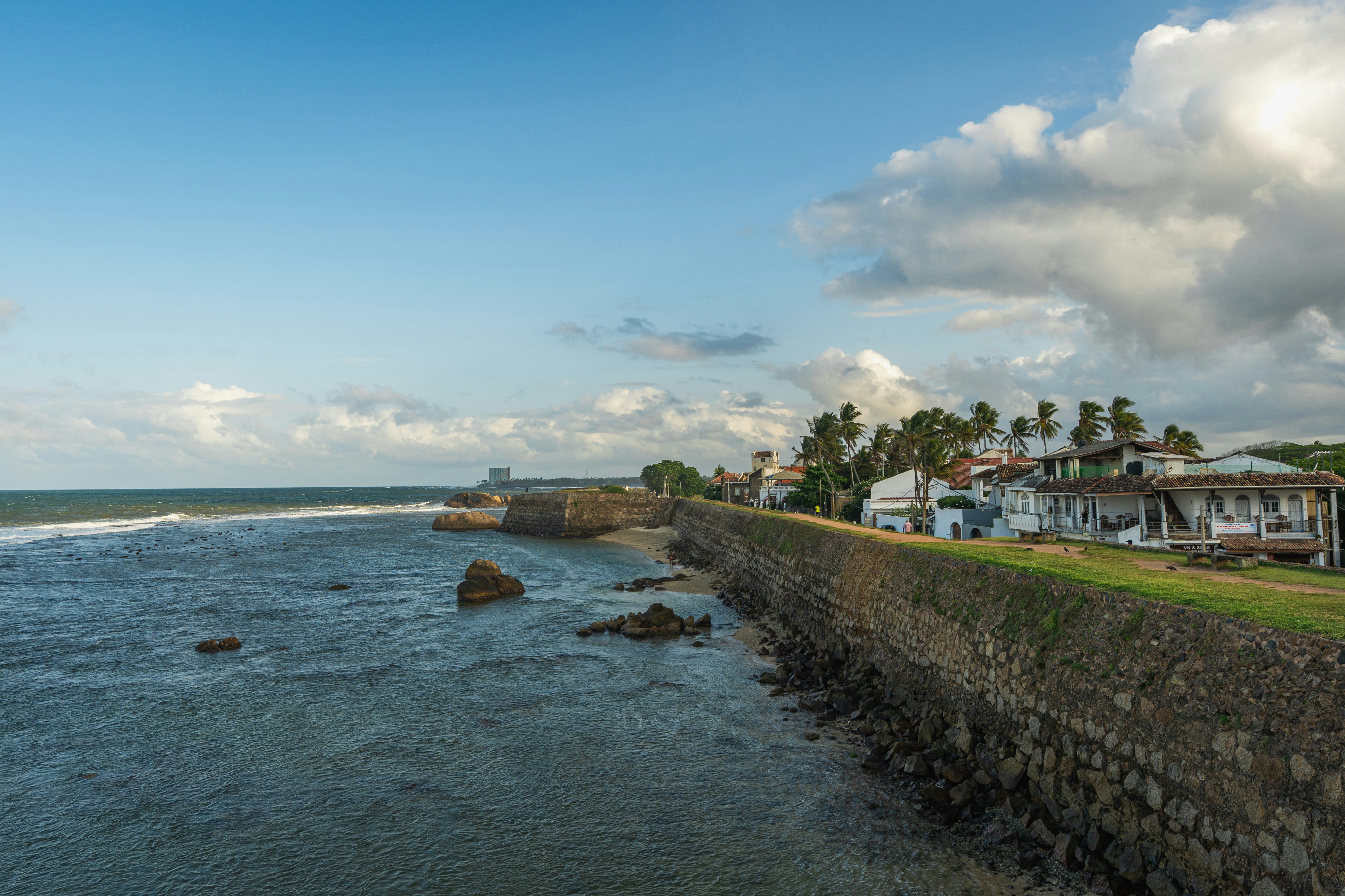 Coastal Breakwater: Houses and Sea Wall Under a Bright Sky
