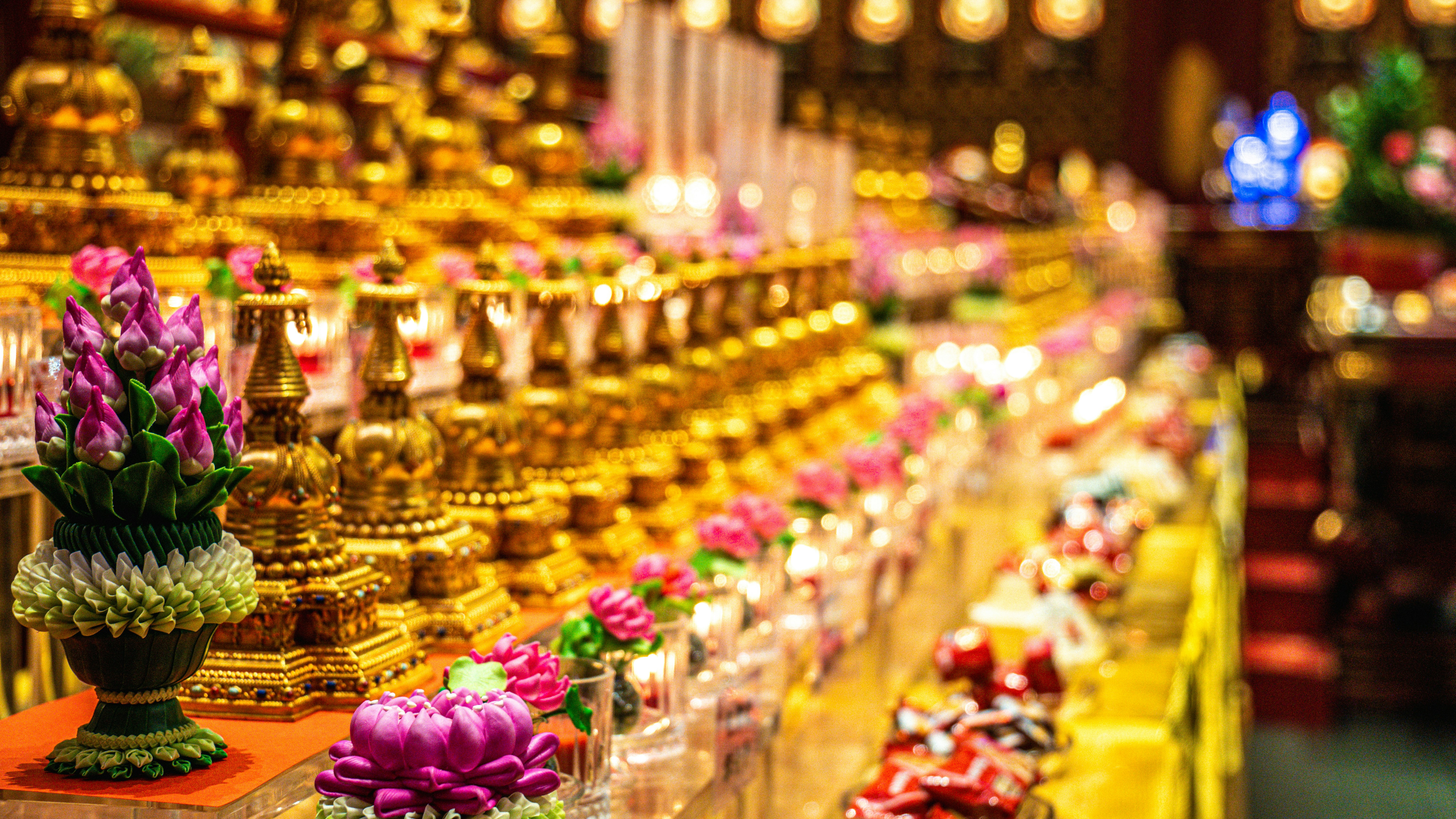 Golden buddha statues and colorful floral offerings in a temple