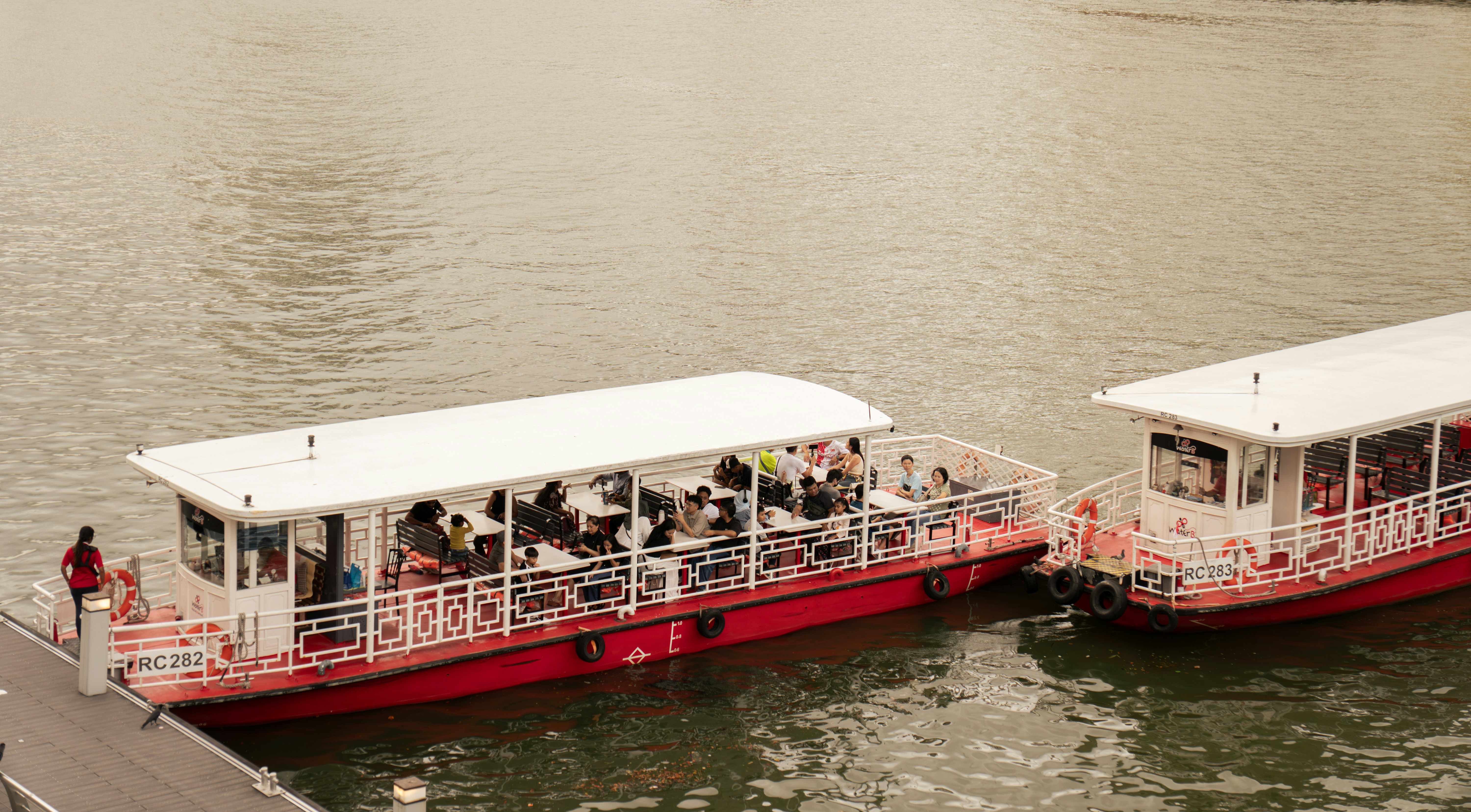 Two red boats with people docked on the water