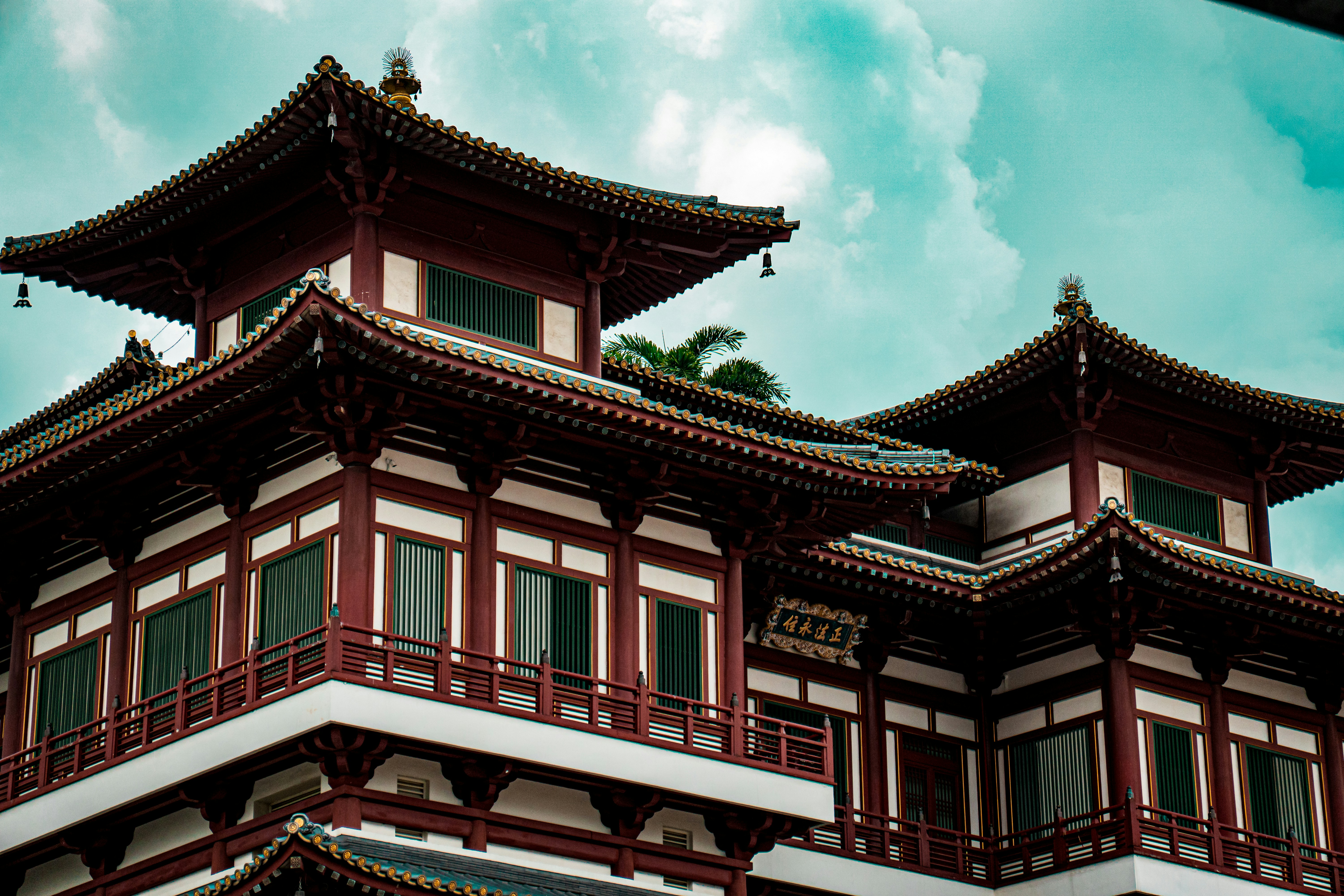 Layered eaves and crimson balconies: a pagoda-inspired facade under a turquoise sky