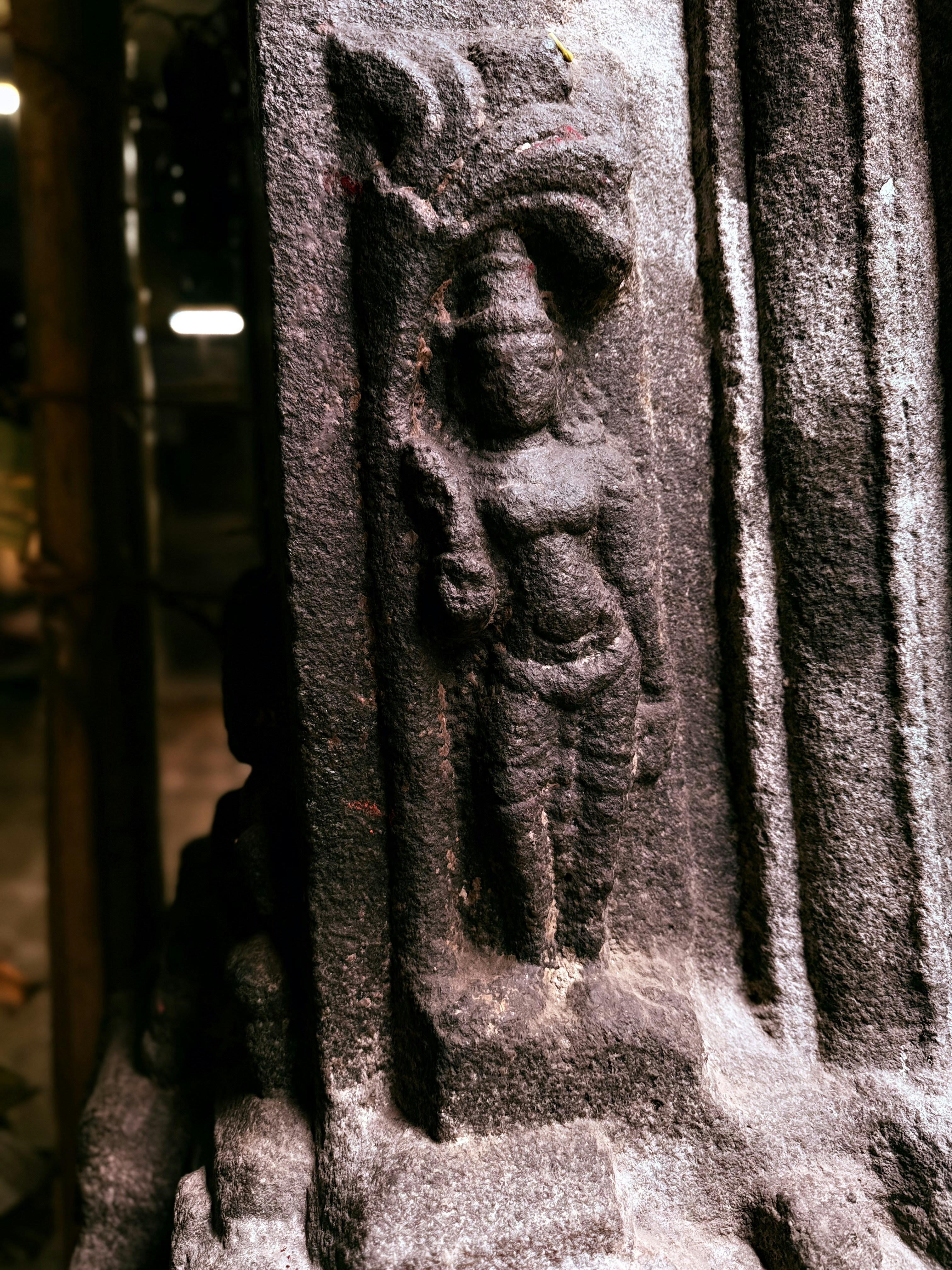 Carved Guardian: A Weathered Stone Figure on a Monumental Column