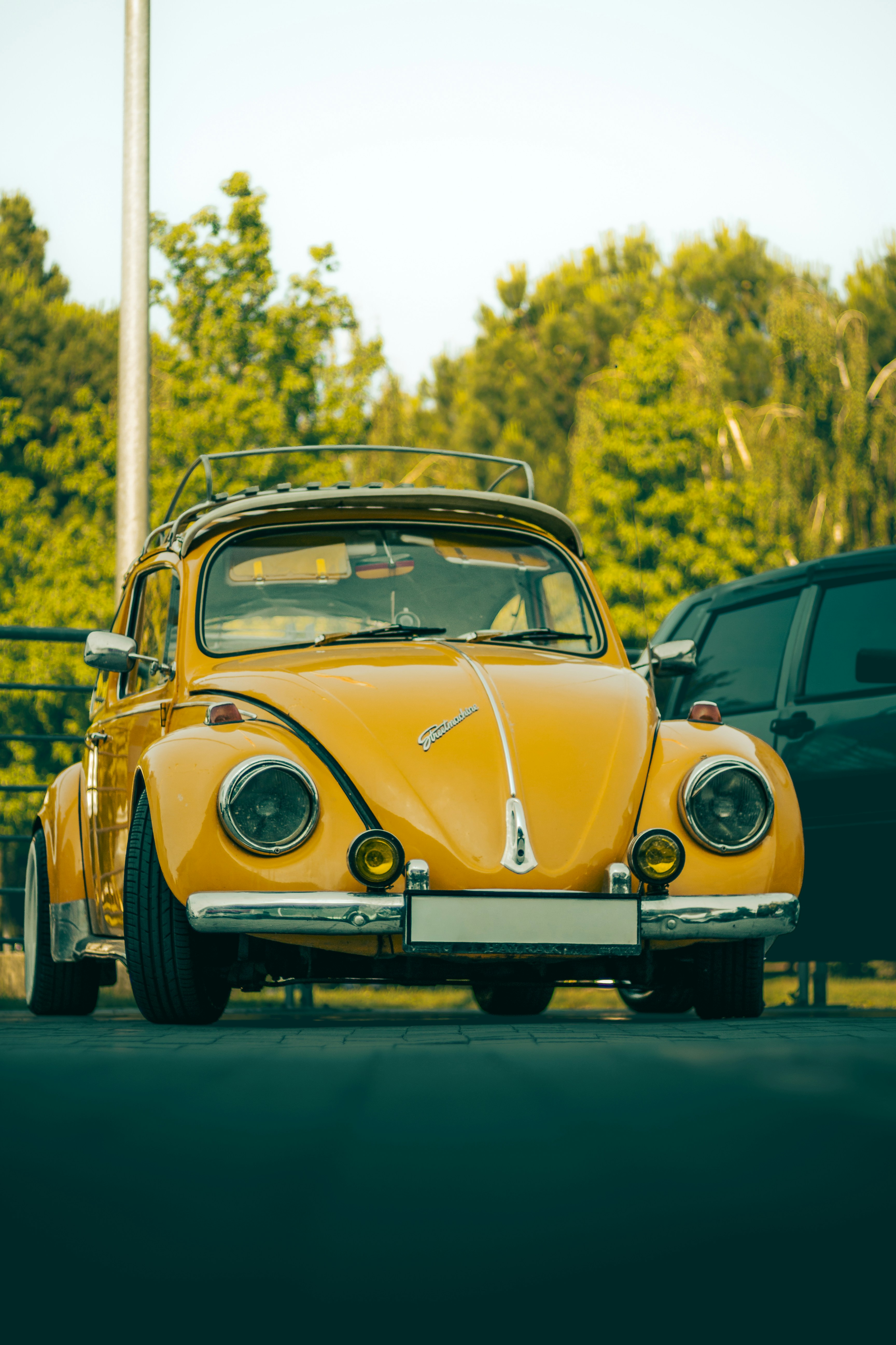 A full frontal cinematic shot of a classic yellow Volkswagen Beetle parked on the street, showcasing nostalgic automotive design, vintage vibes, and a moody autumn backdrop in Bursa, Turkey.
