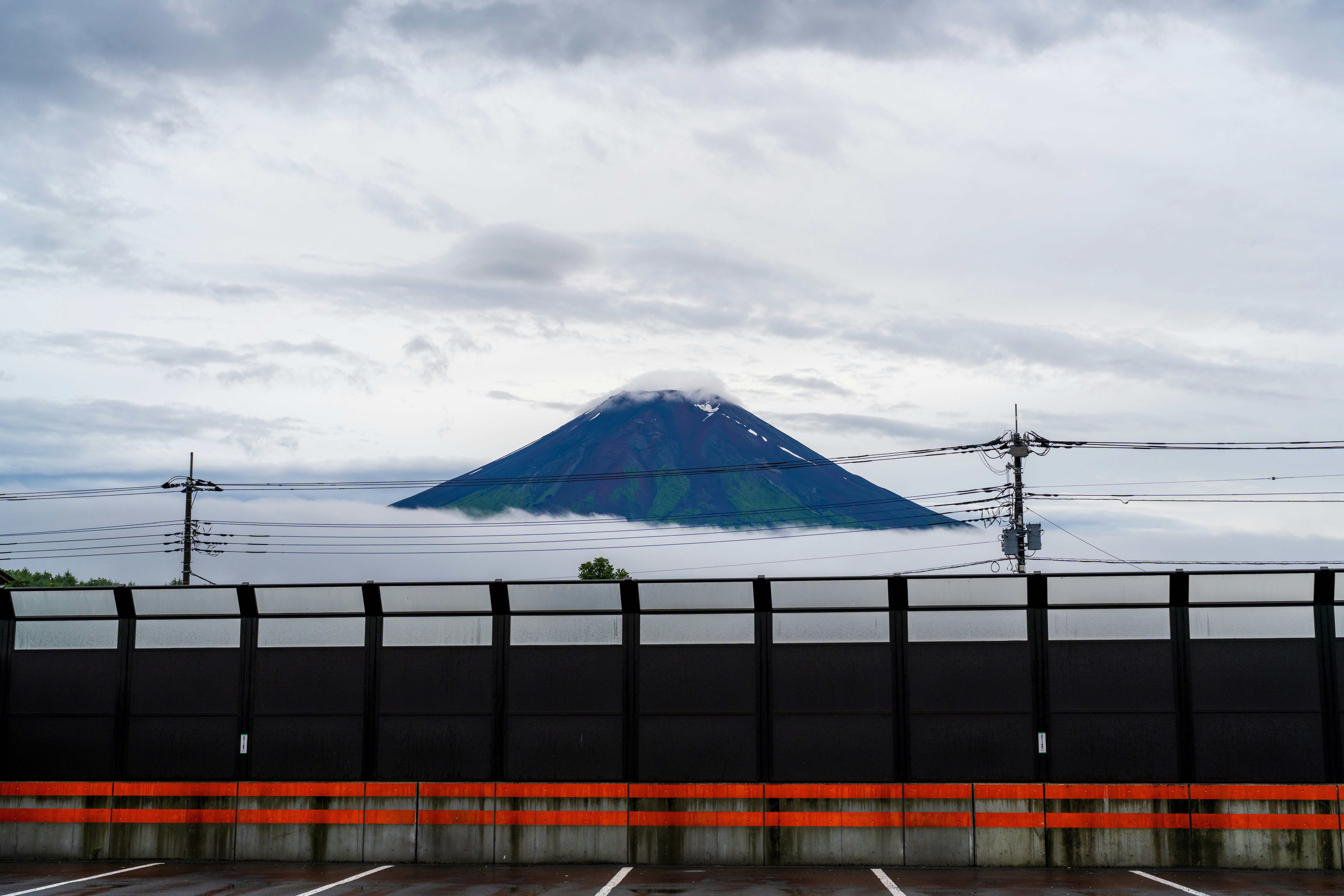 Mt. Fuji peeking over a highway barrier at dawn