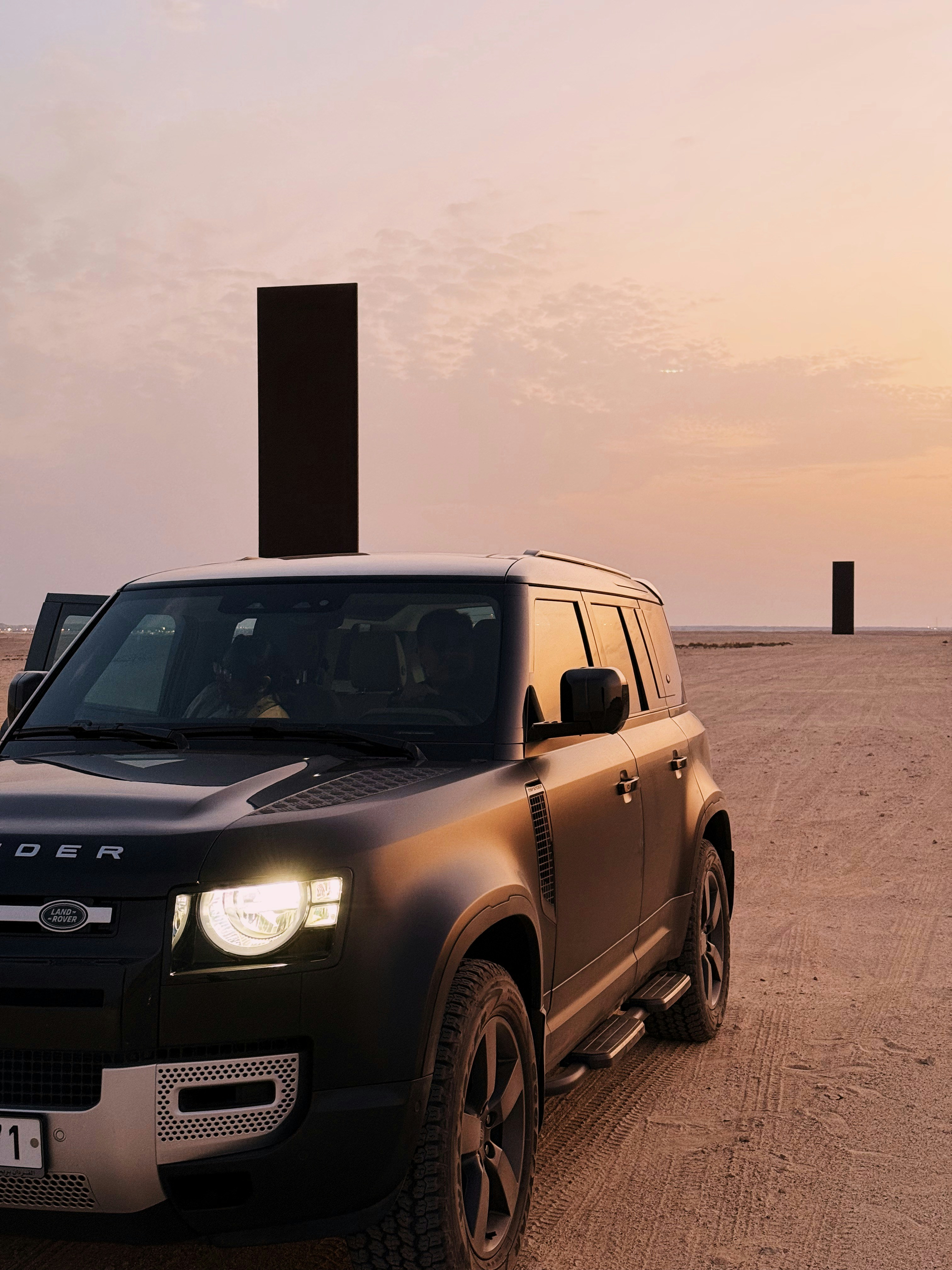 Desert Drive: The Black SUV and the Silent Monoliths at Sunset
