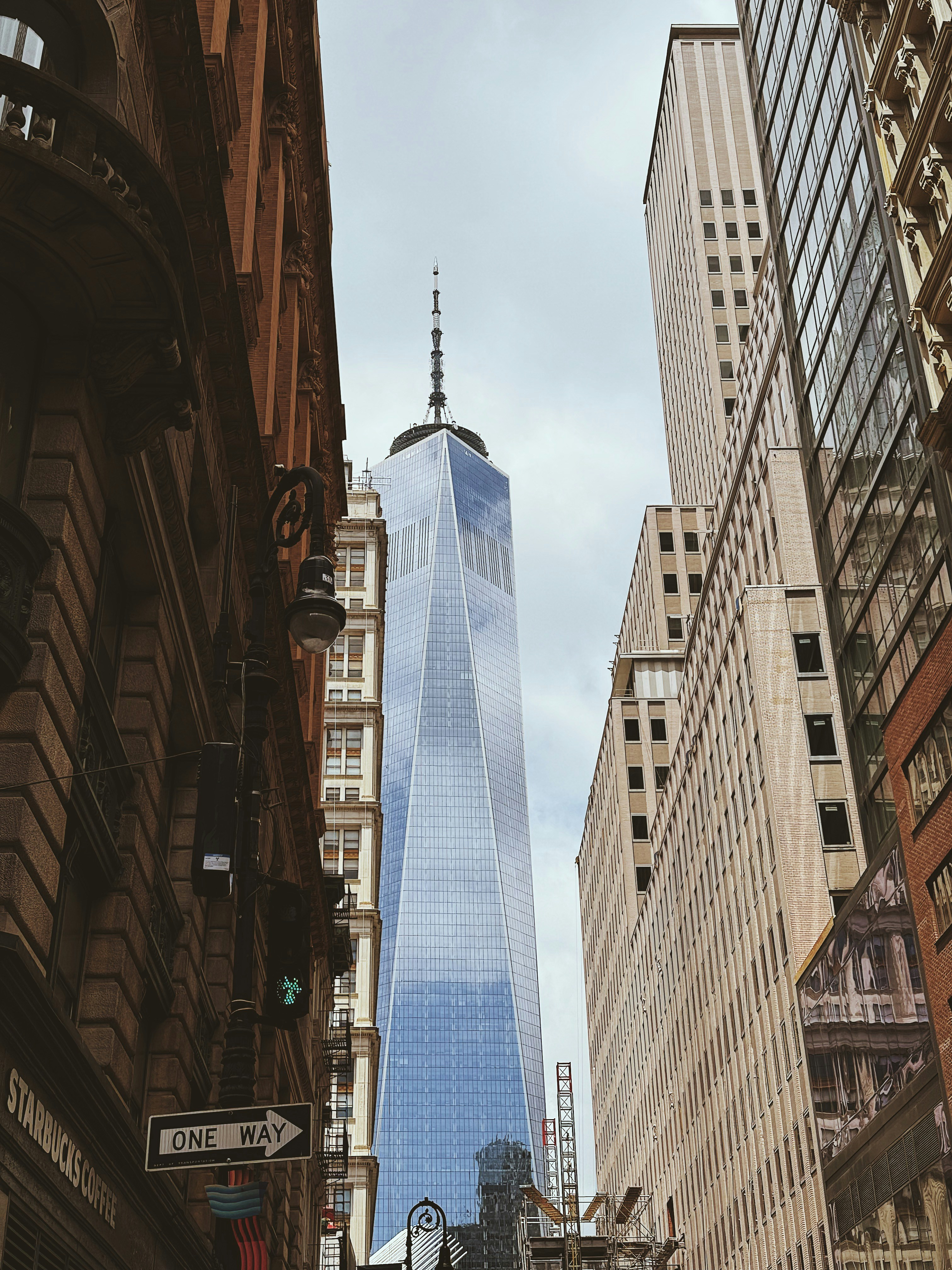 Skyward Glass: One World Tower Rising Between Narrow Canyoned Streets