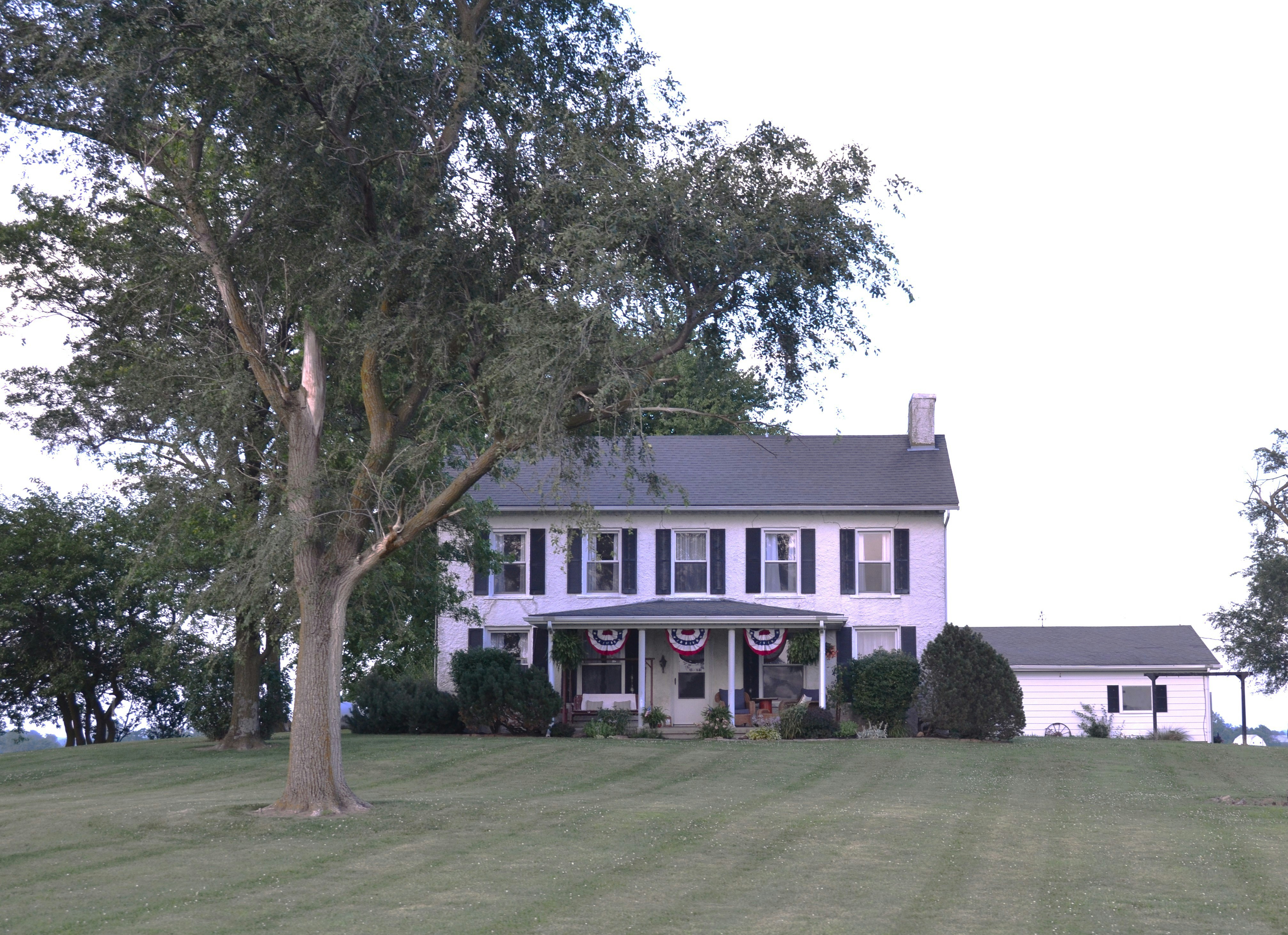Colonial House on a Gentle Hill with Patriotic Porch Decorations