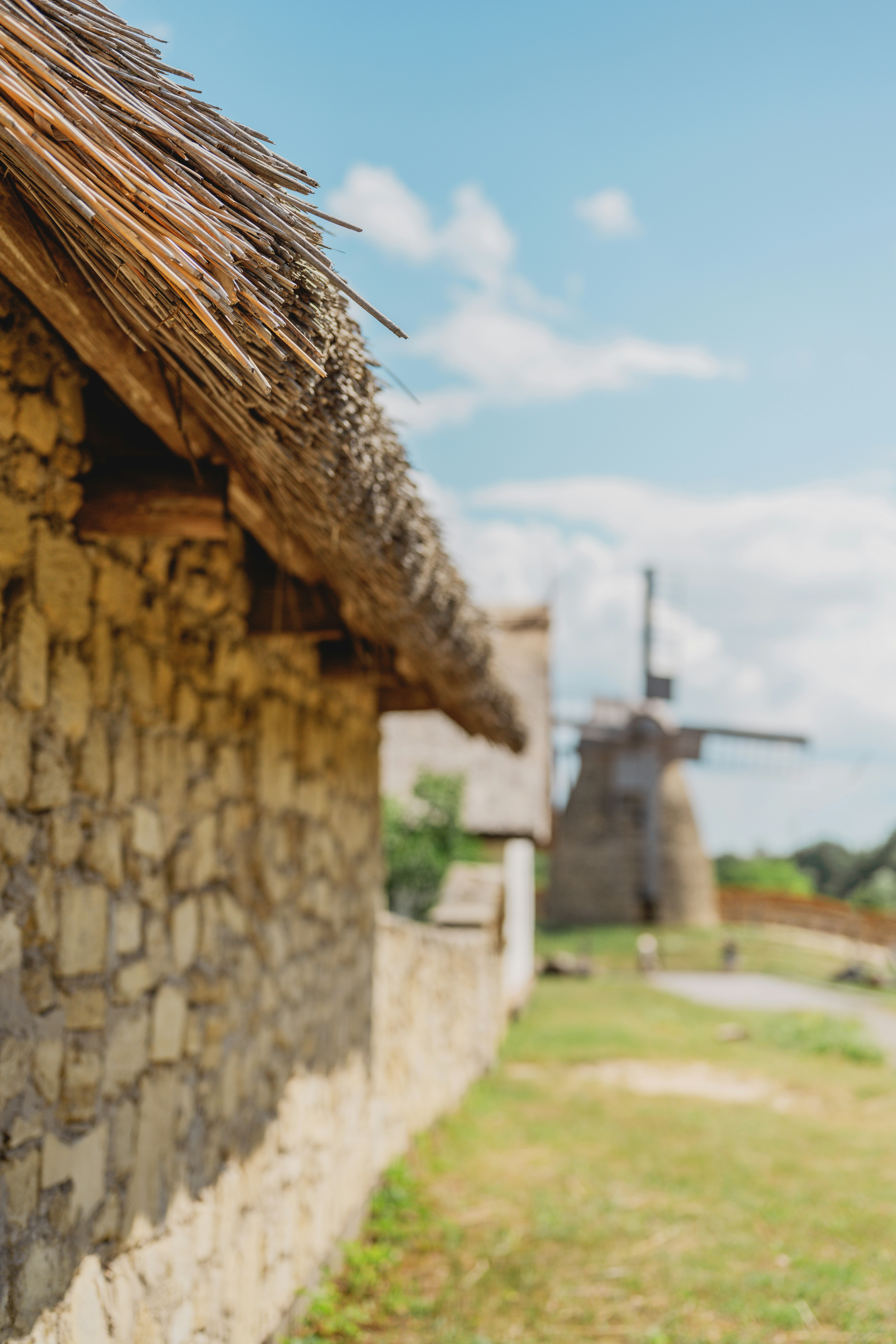 Thatched Roof and Stone Wall Leading to a Windmill Vista