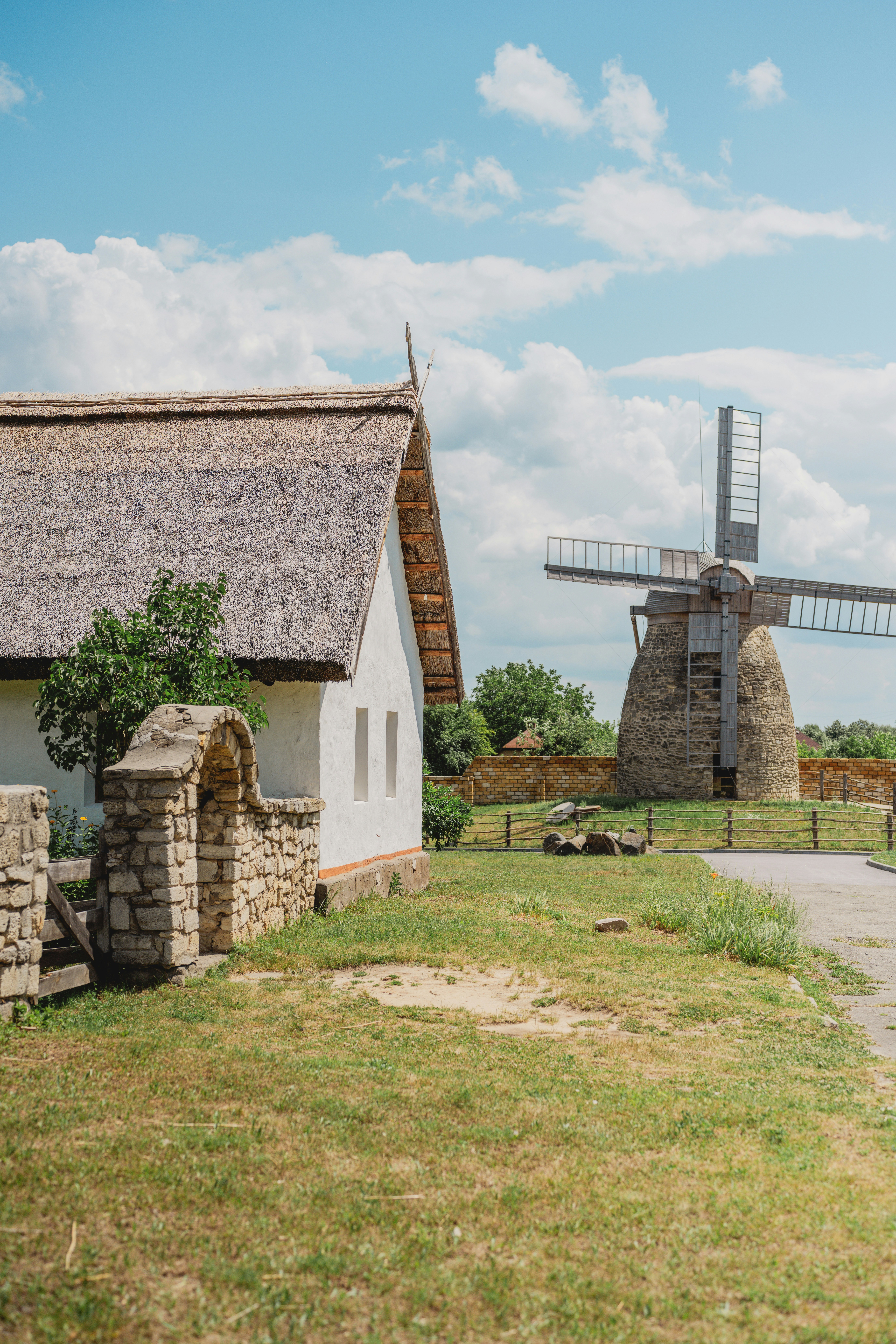 Windmill and thatched-roof cottage under a bright blue sky