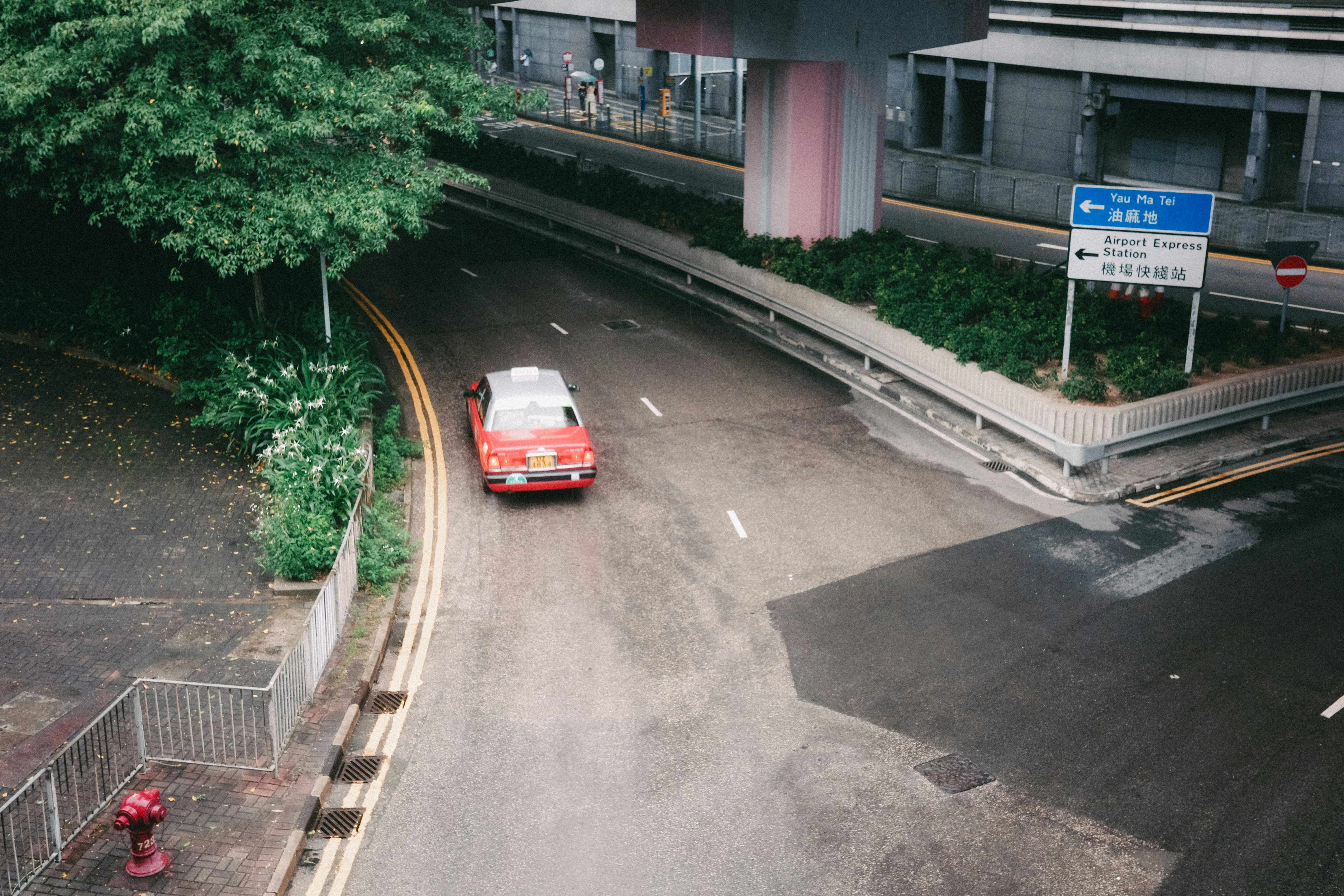 Turn Under the Overpass: A Red Car Navigates a Quiet City Curve