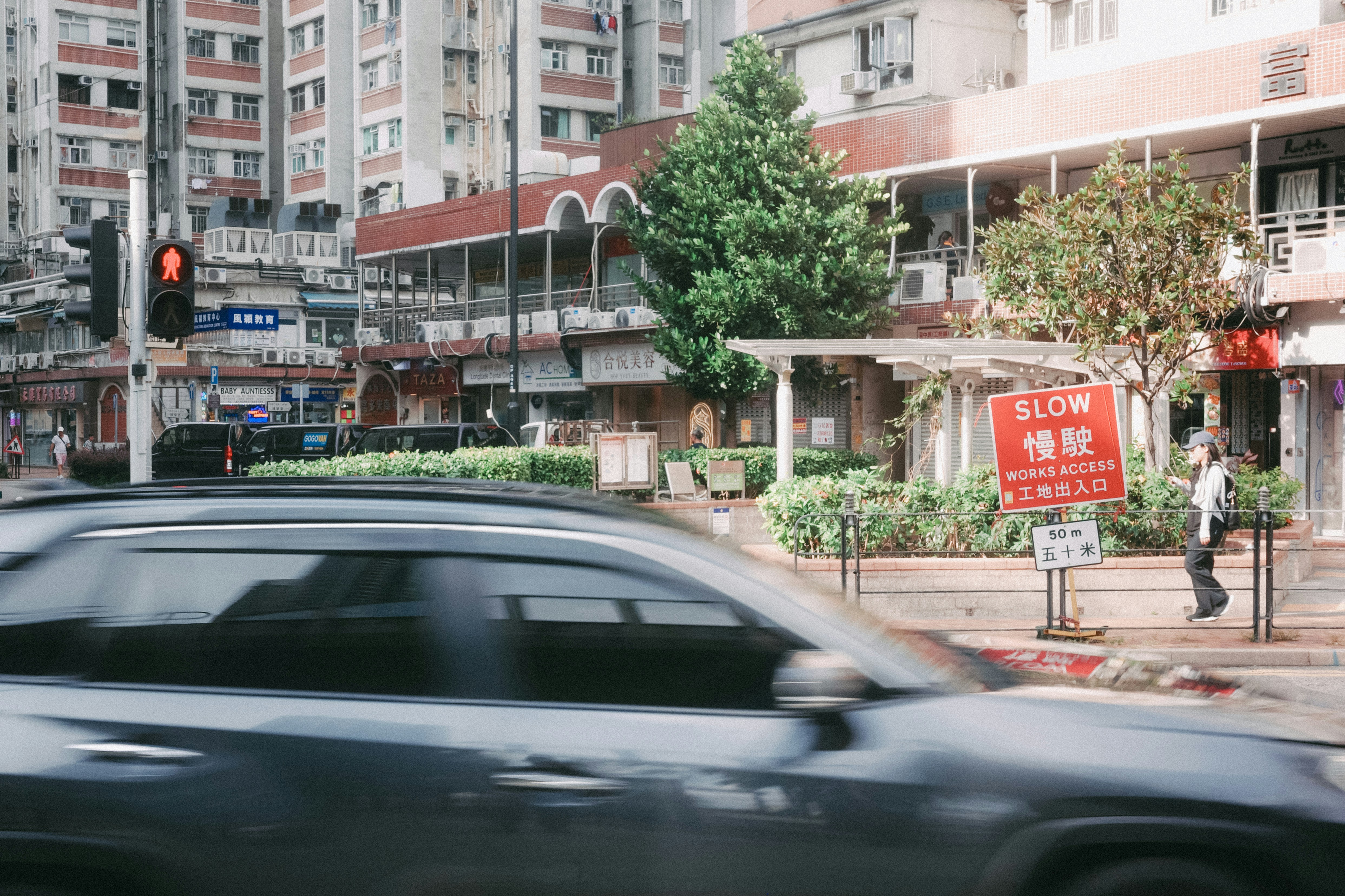 Motion blur and urban rhythm: car streaks past a sunlit city block