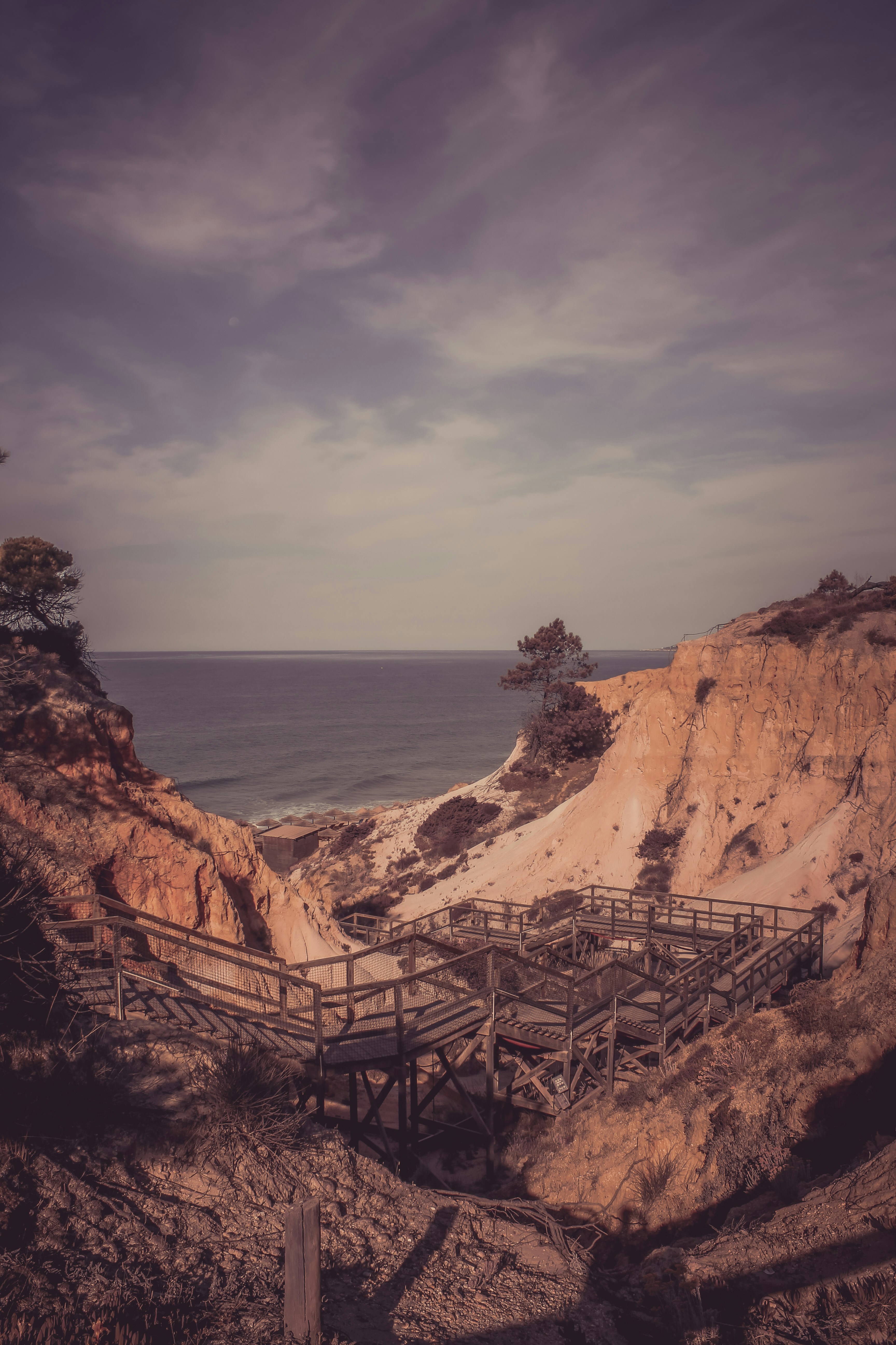 Wooden coastal stairway weaving into a sunlit cliffside panorama