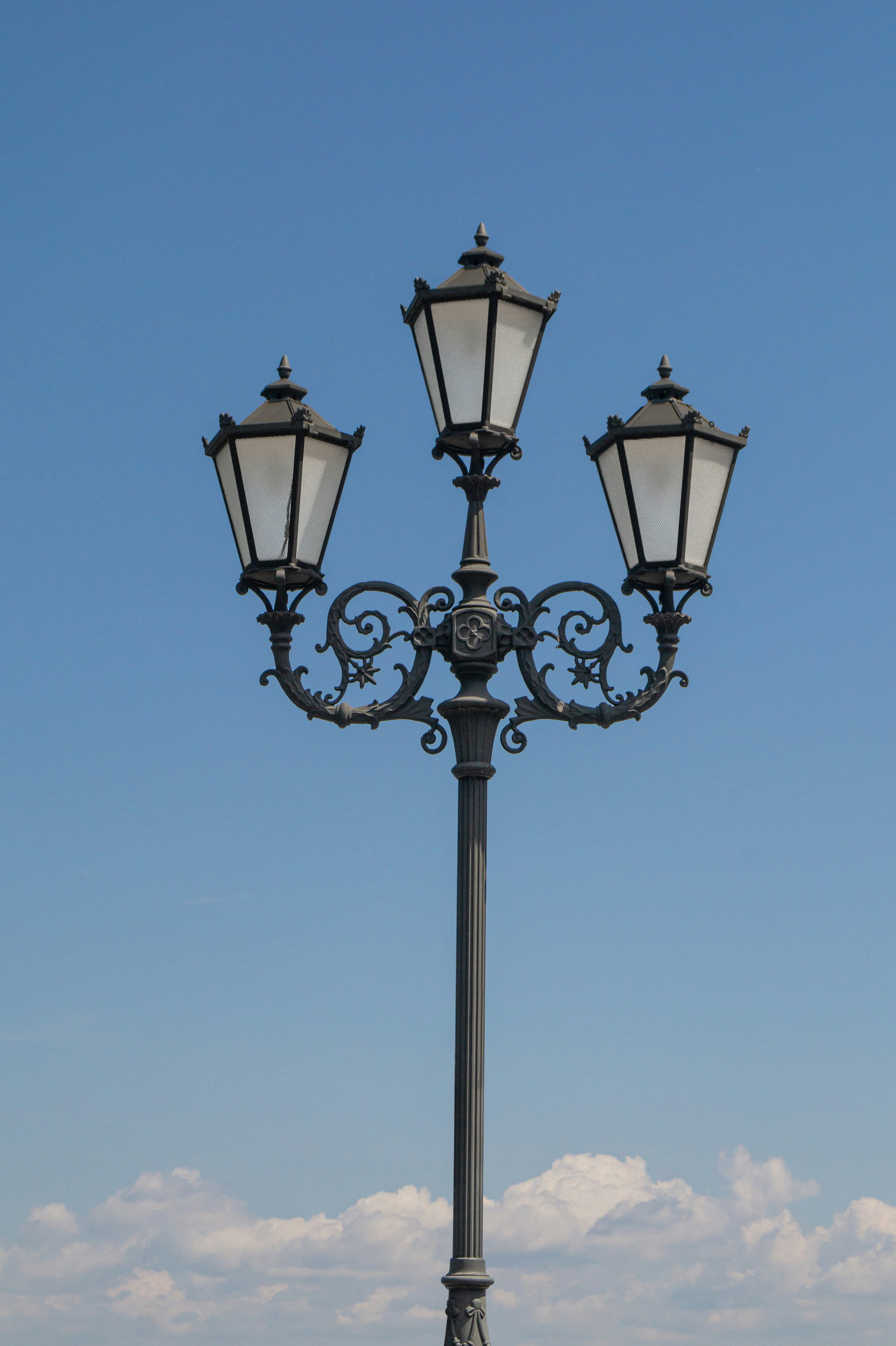 Elegant Three-Lamp Ivy-Clad Street Lantern Reaching Toward a Clear Sky