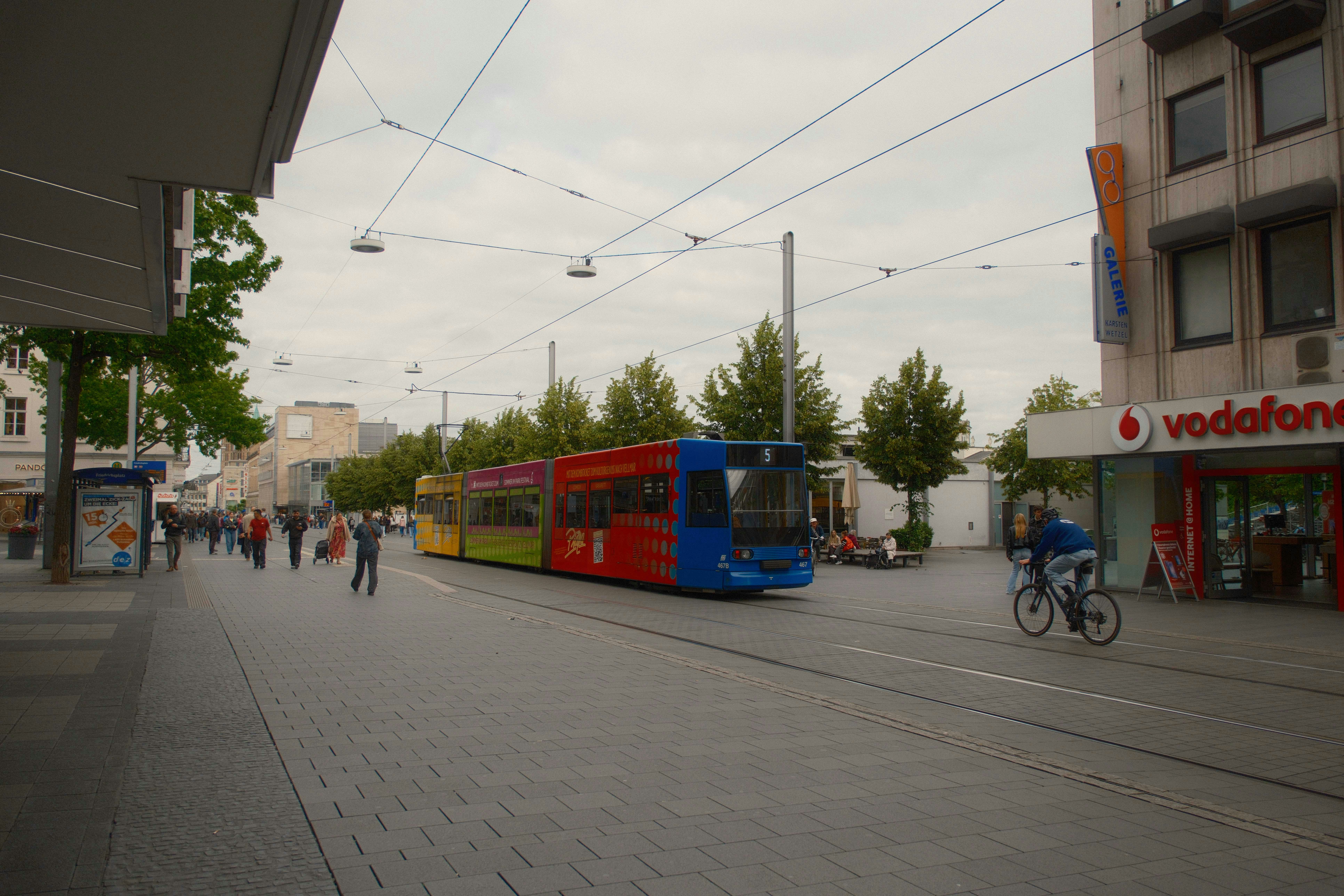 City tram in motion: red and blue carves through a pedestrian plaza