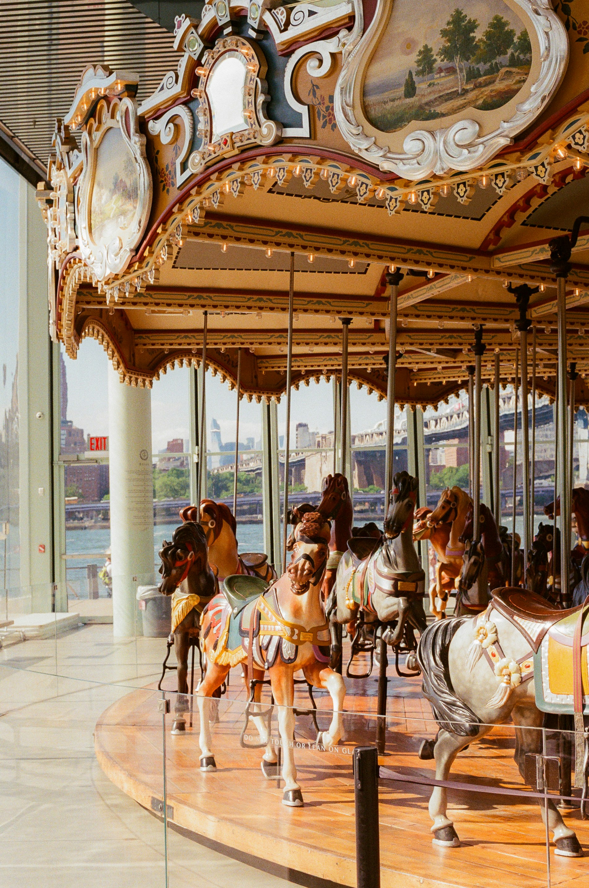 A vintage carousel glowing in the afternoon light, with painted horses, mirrors, and city views creating a nostalgic childhood atmosphere.