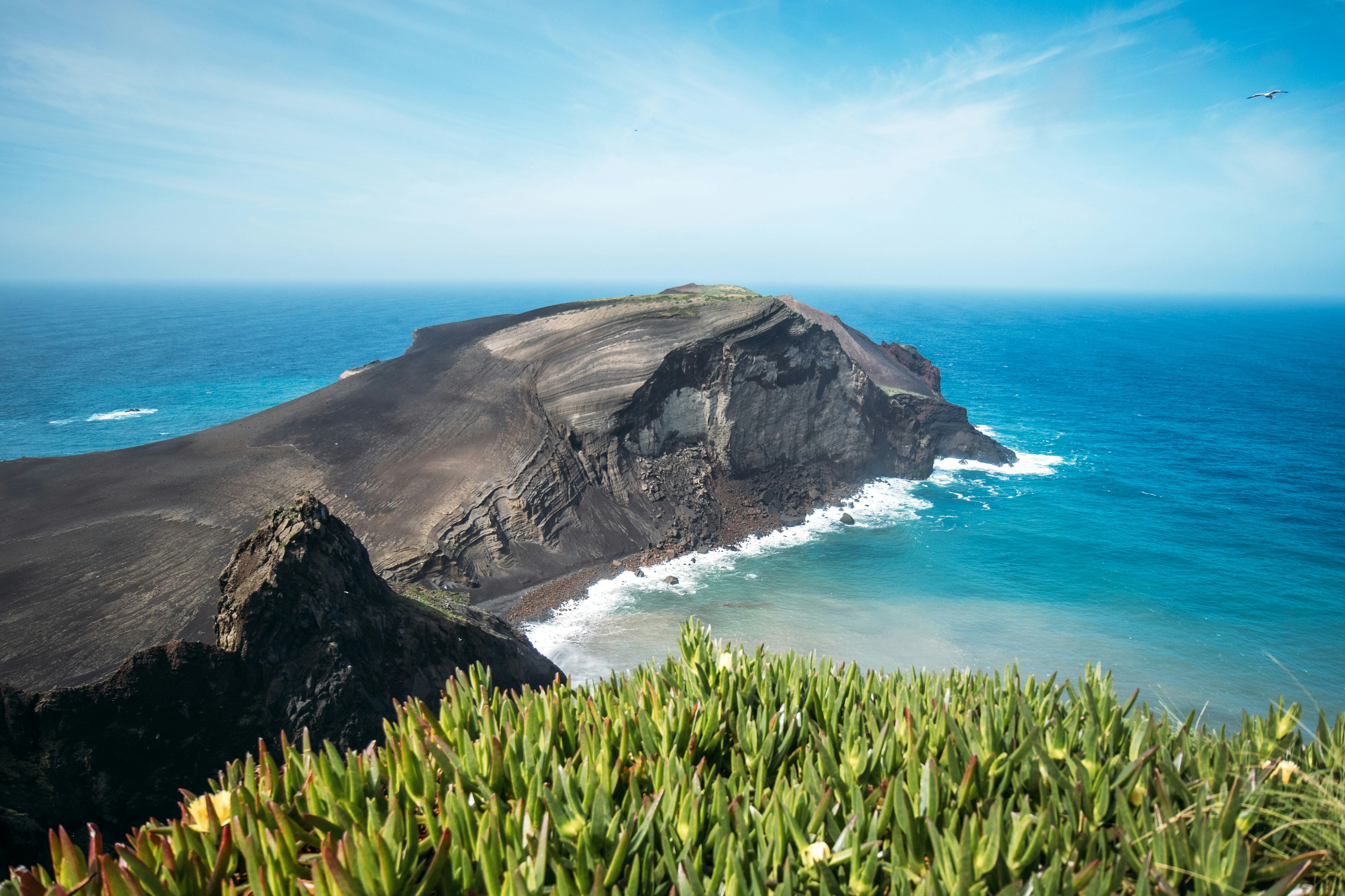Lava Ridge and Azure Sea: Coastal Promontory Framed by Green Cliff Edge
