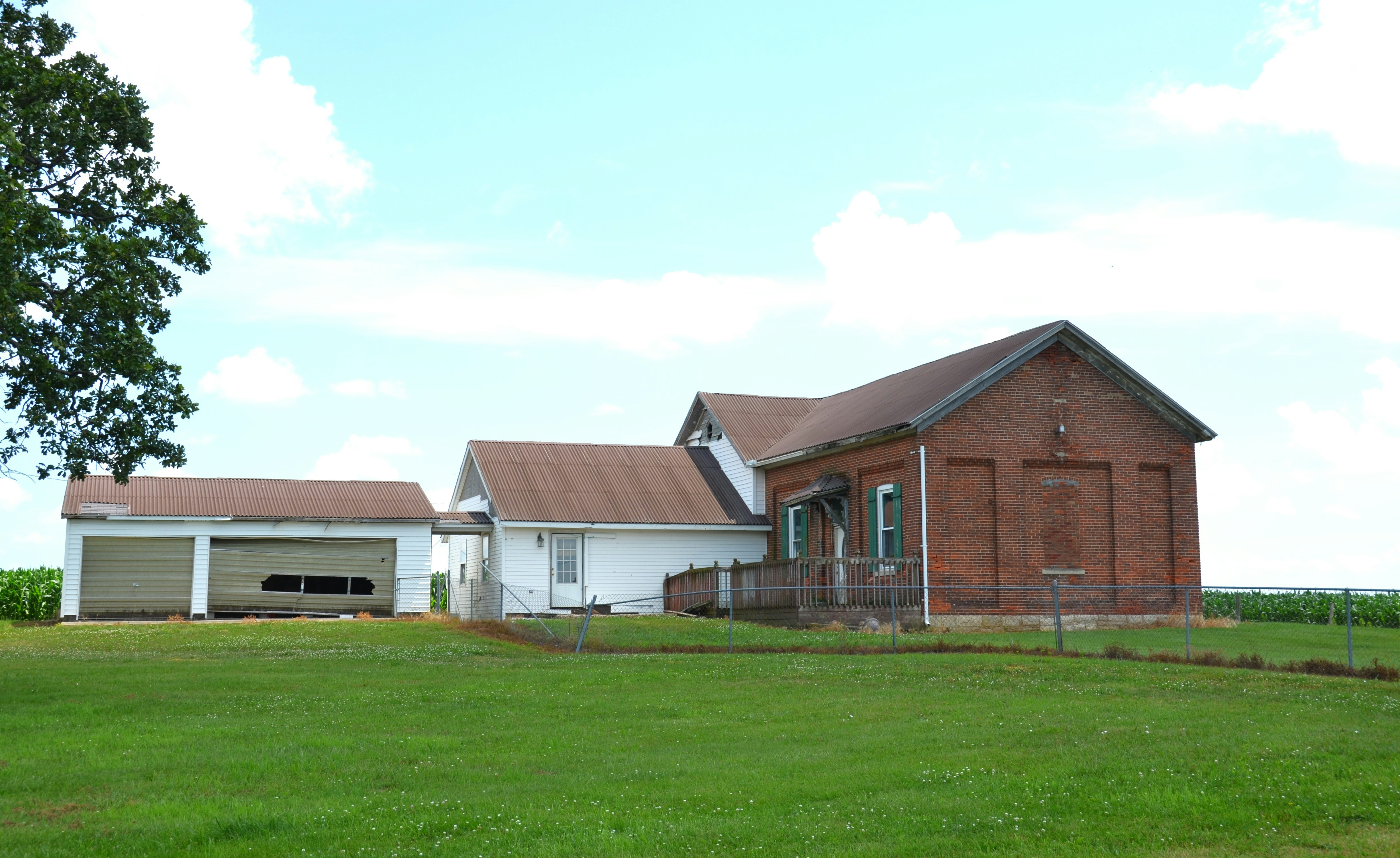 Brick Farmhouse with White Outbuildings under a Broad Blue Sky