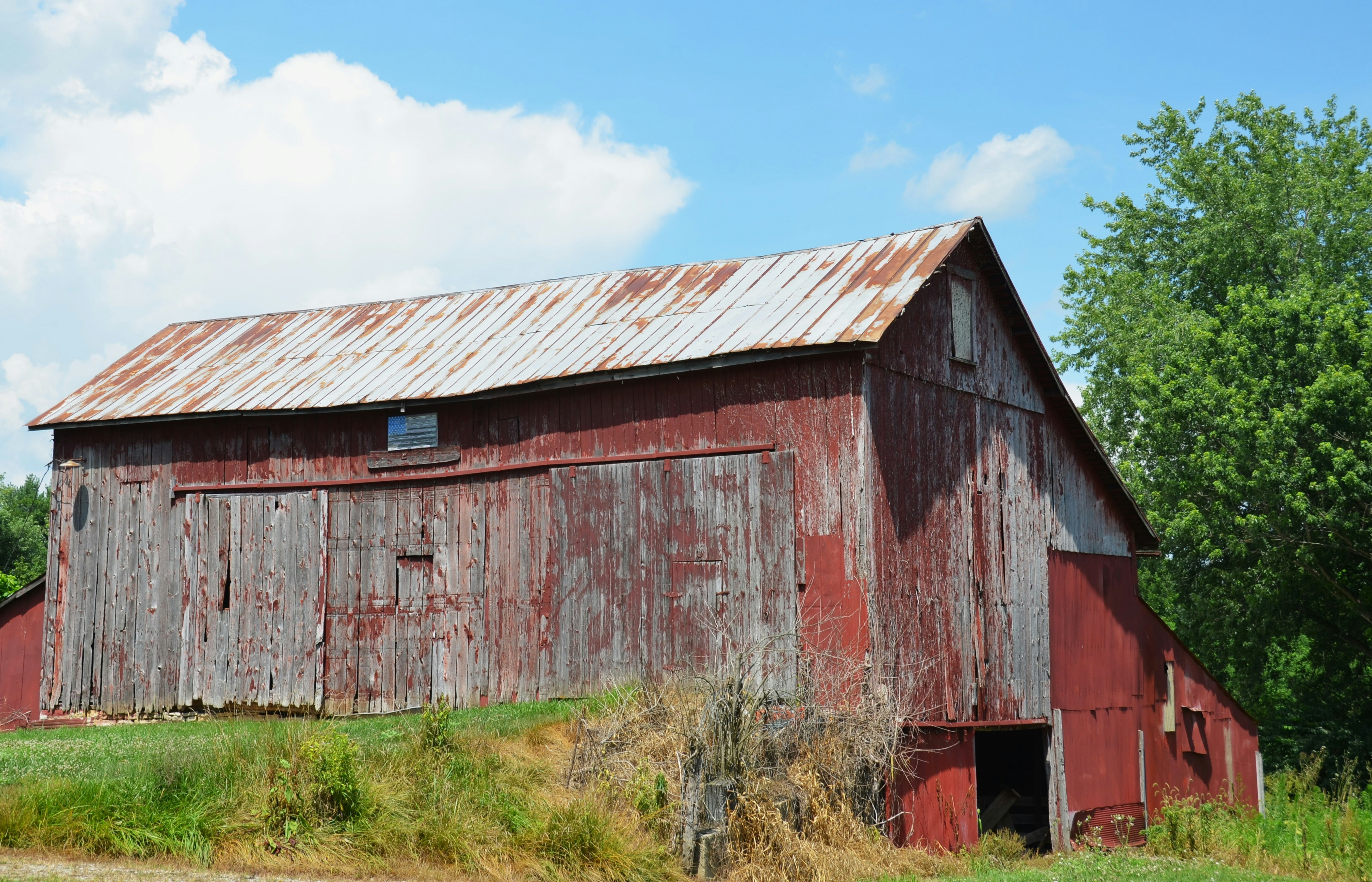 Badly faded red bank barn