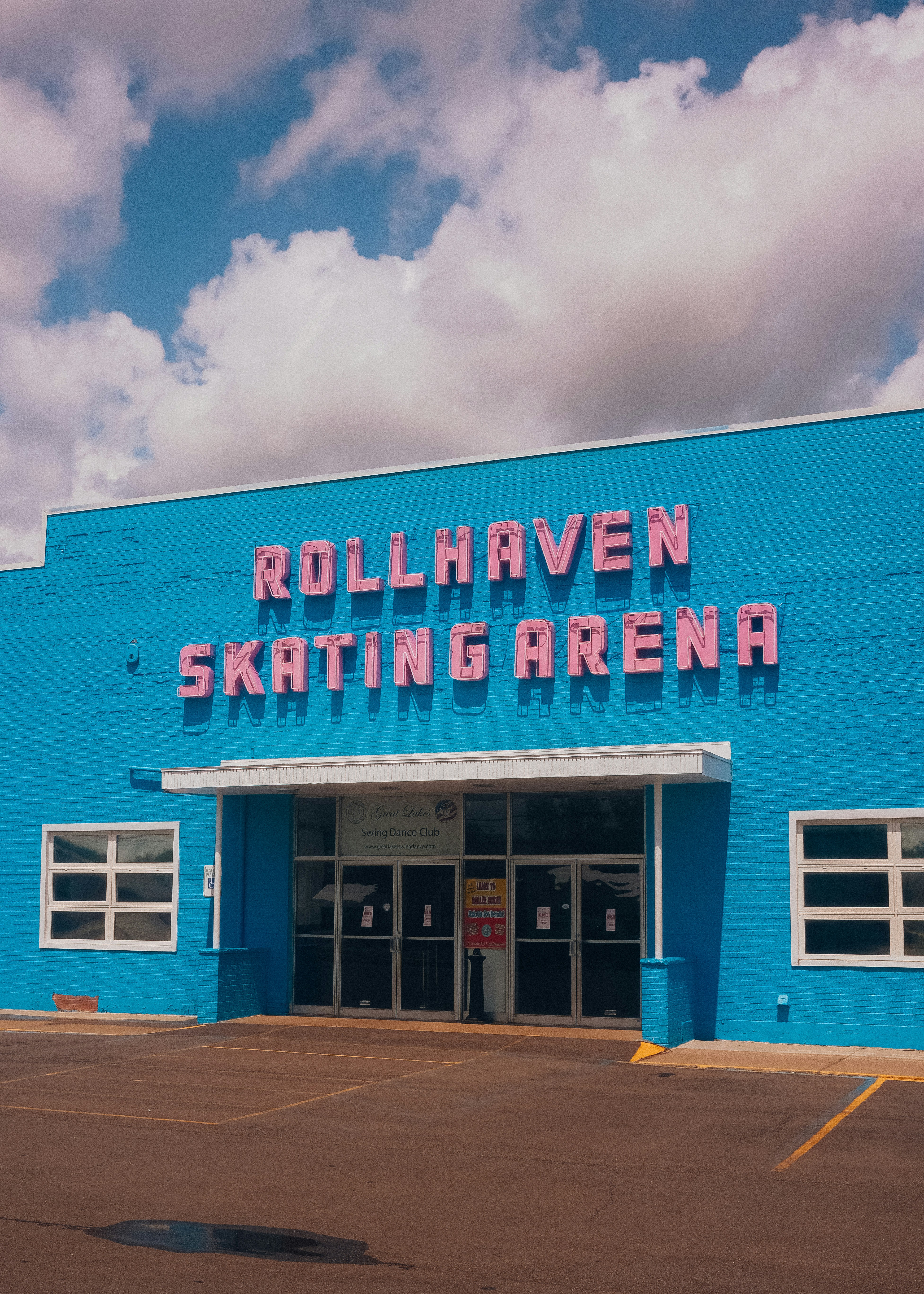 Blue Facade, Bold Signage: Rollhaven Skating Arena Under A Sky of Clouds