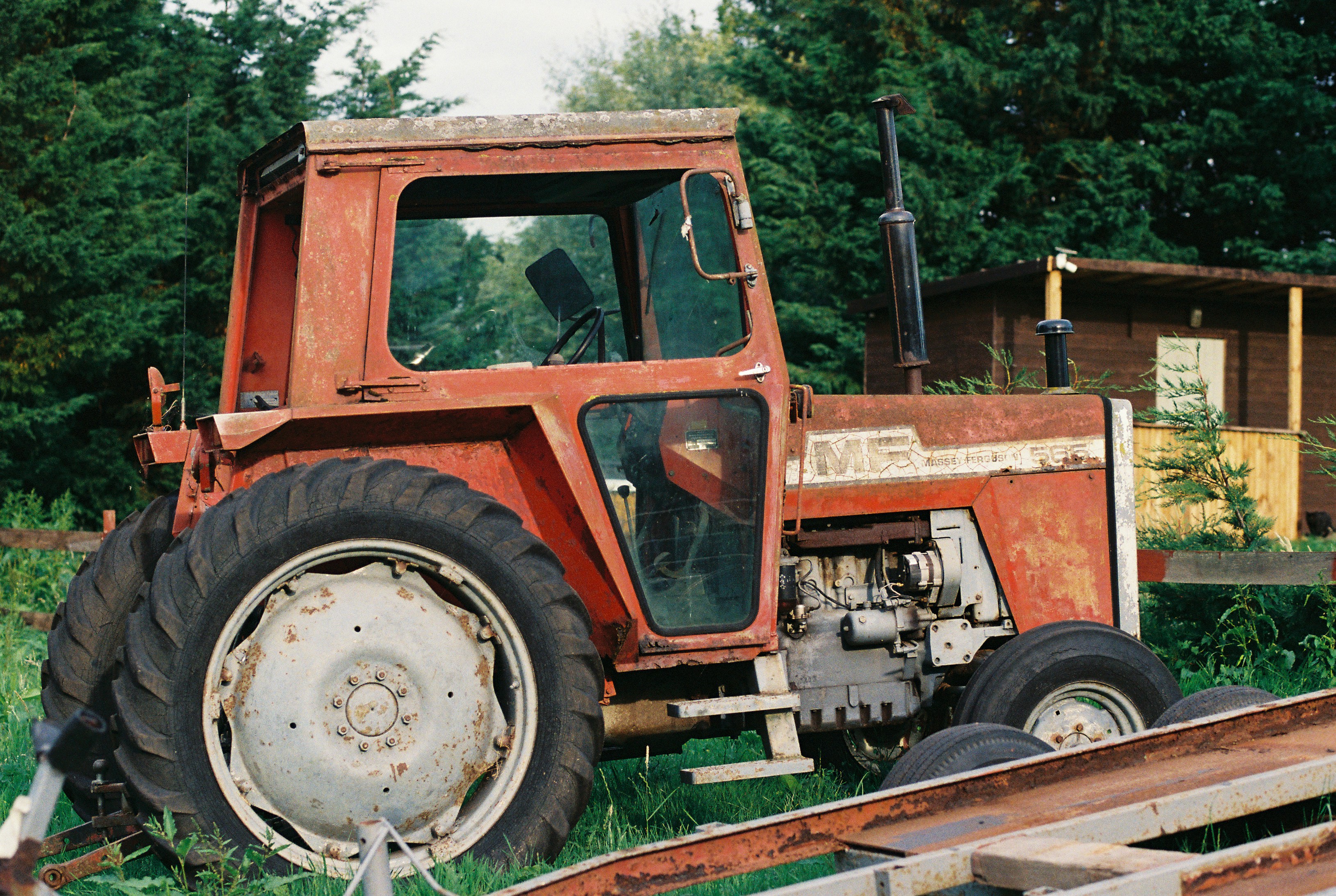 Red Sentinel on Rails: An Abandoned Tractor Resting by the Tracks