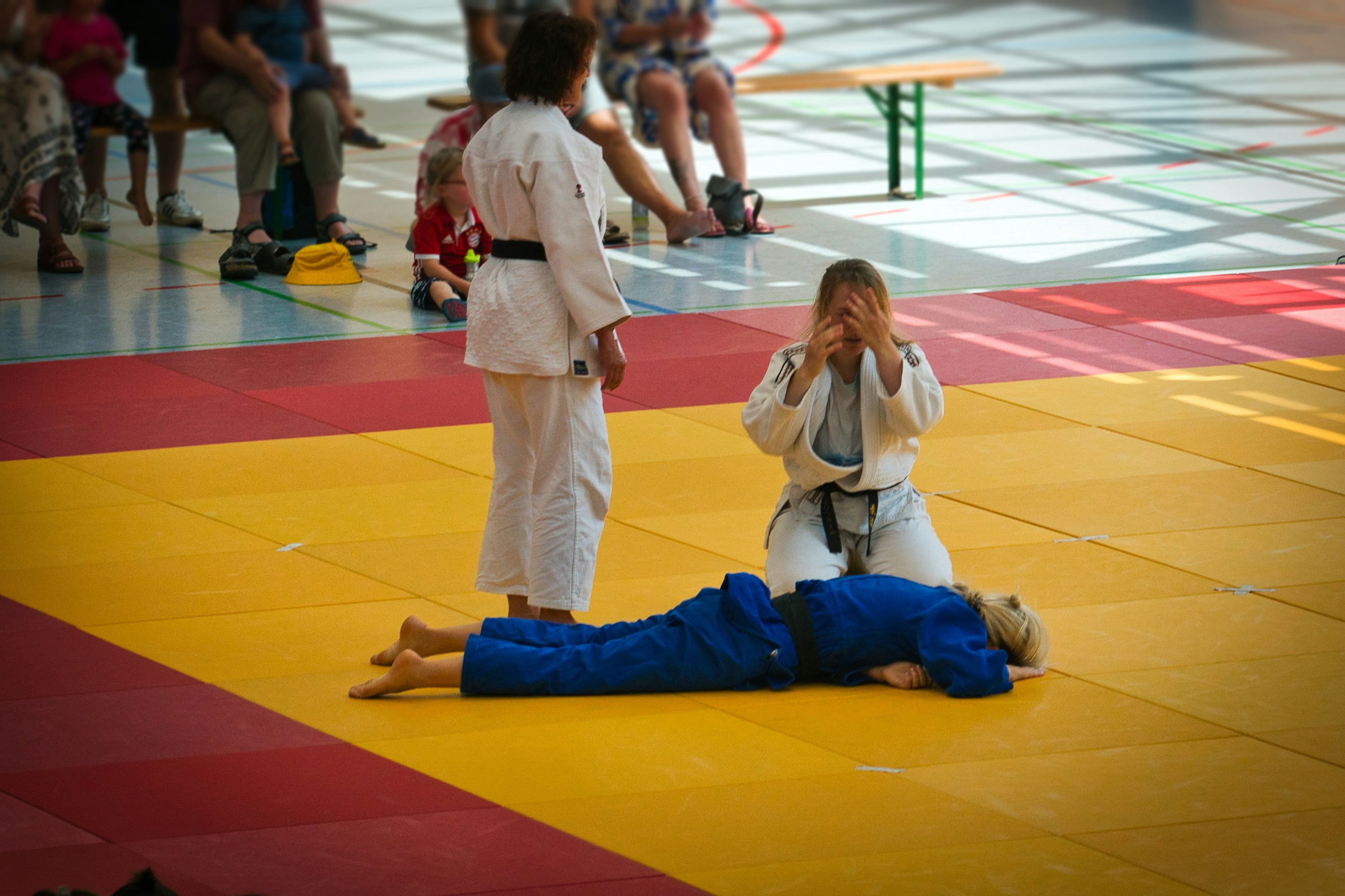 Grounded Judo Moment: Practitioners in a Sunlit Gym Surrounded by Spectators