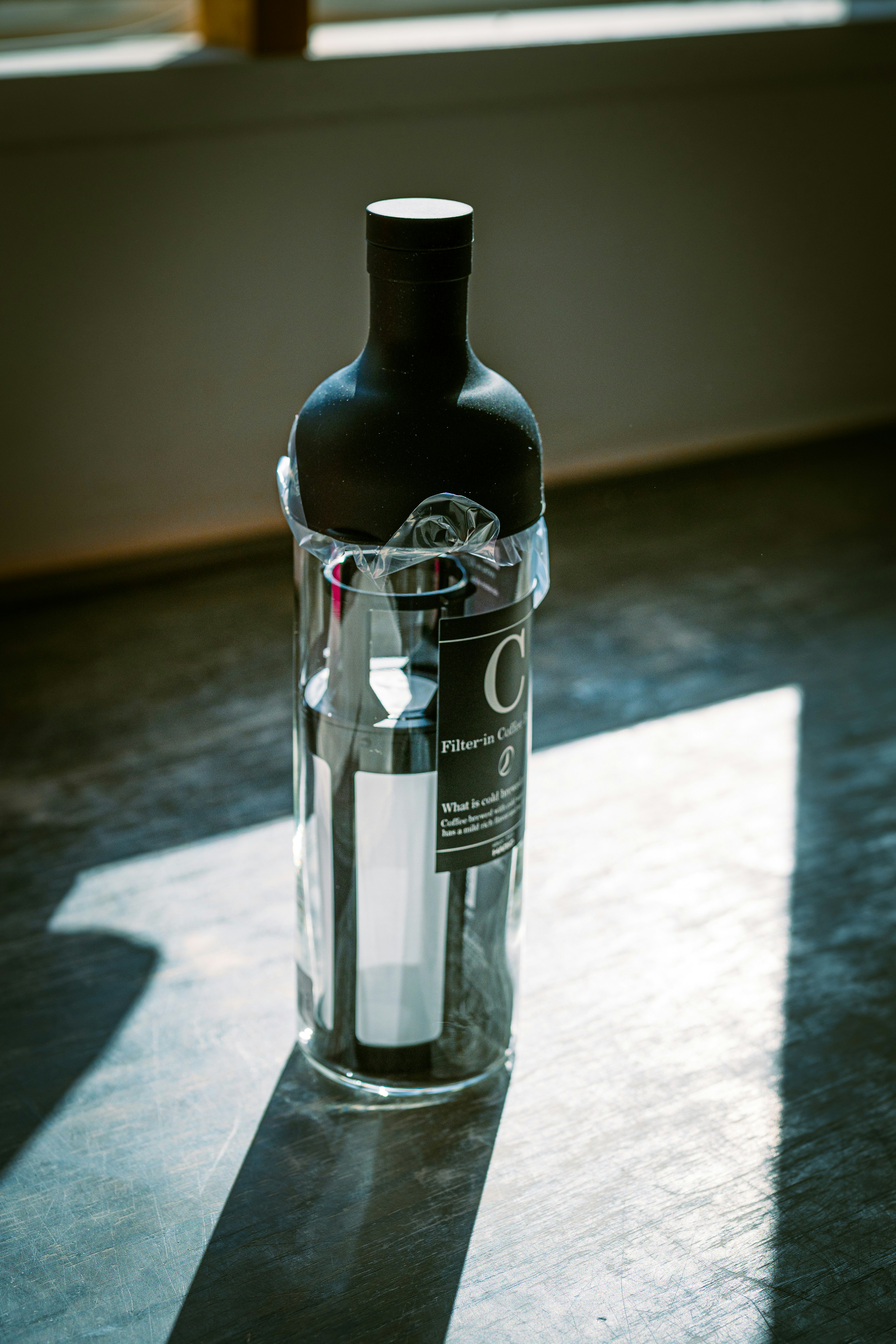Still Life of a Dark Bottle with Cardboard Label in Soft Window Light