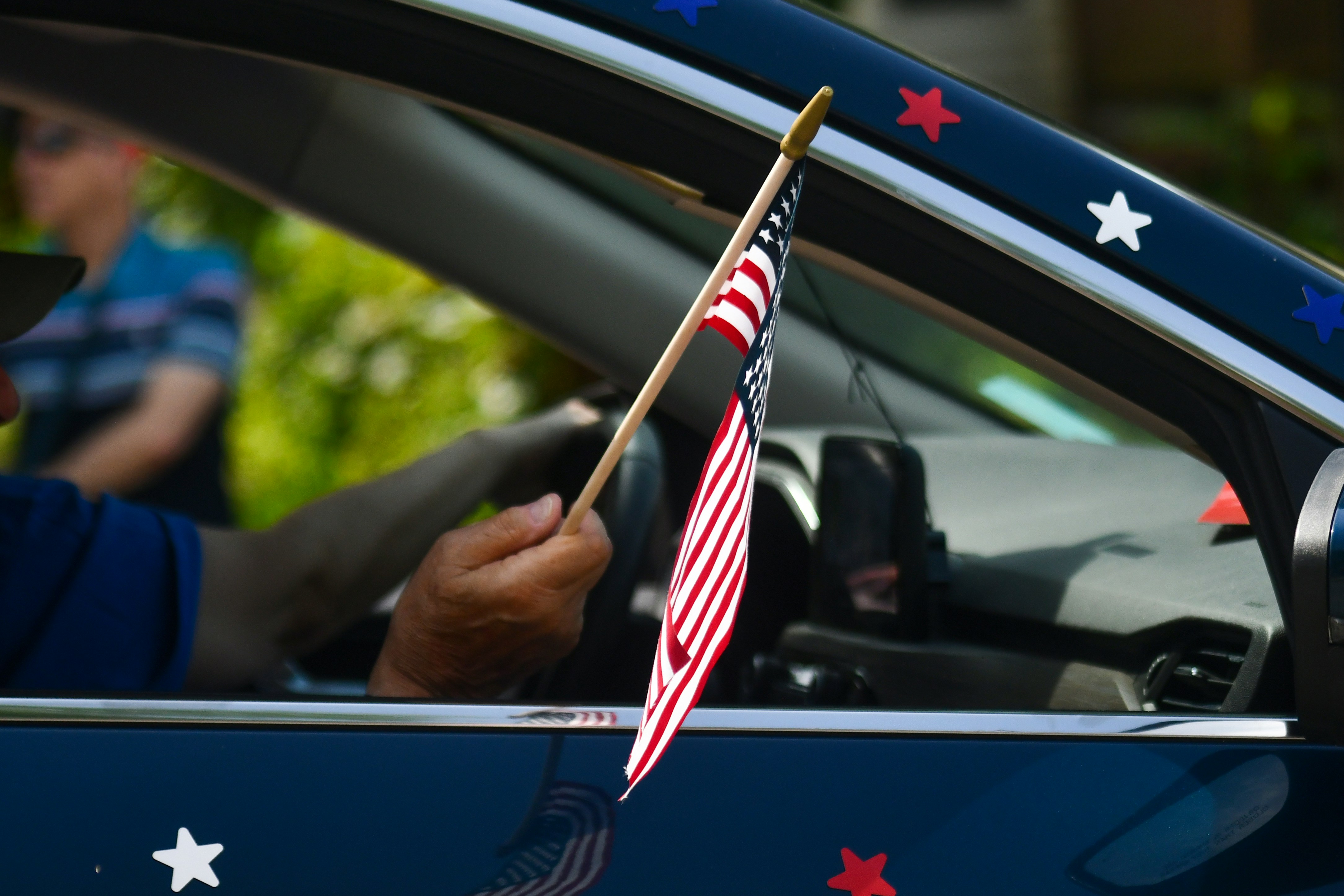 Flag and hand in a patriotic car window