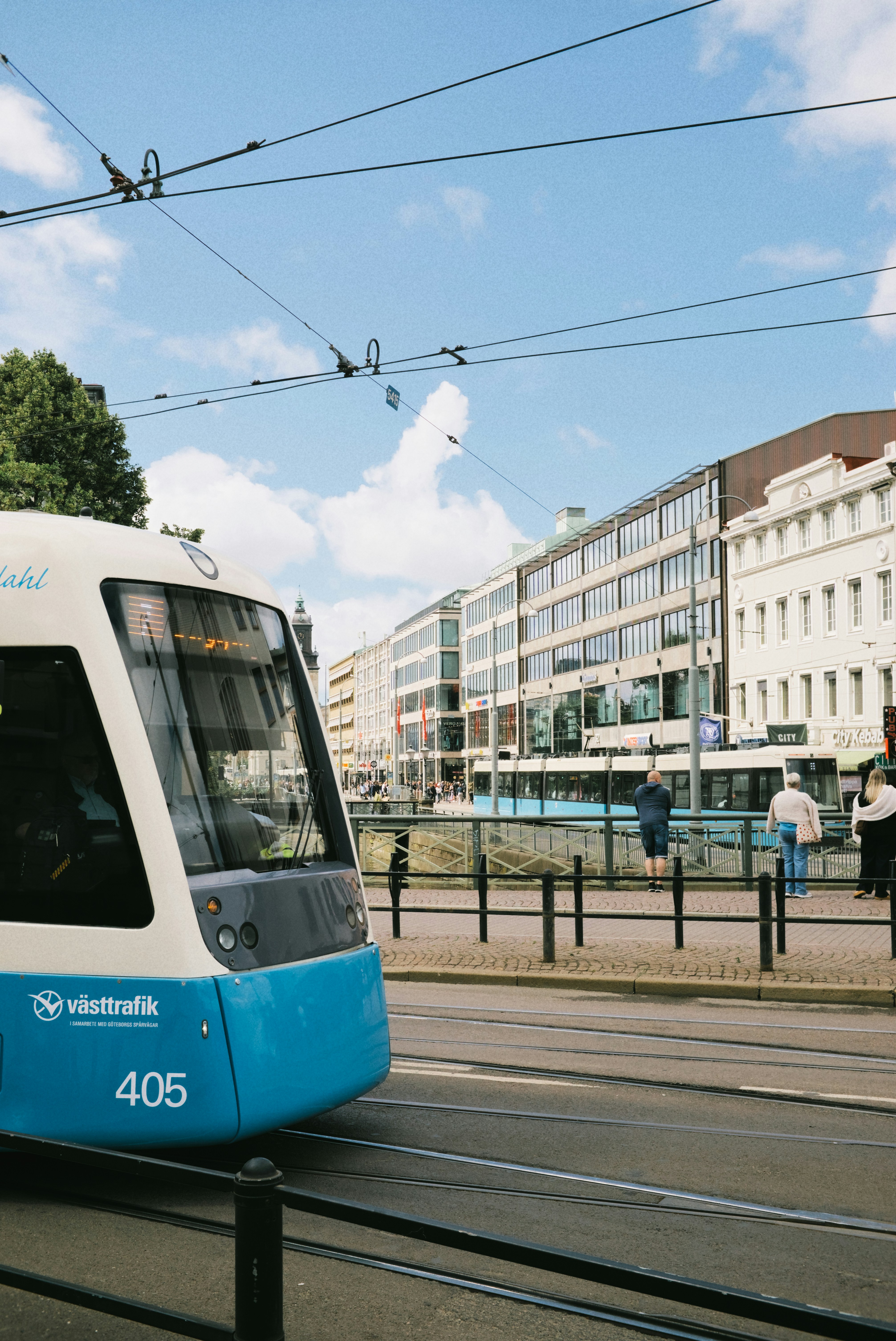 Blue tram at a sunlit urban waterfront