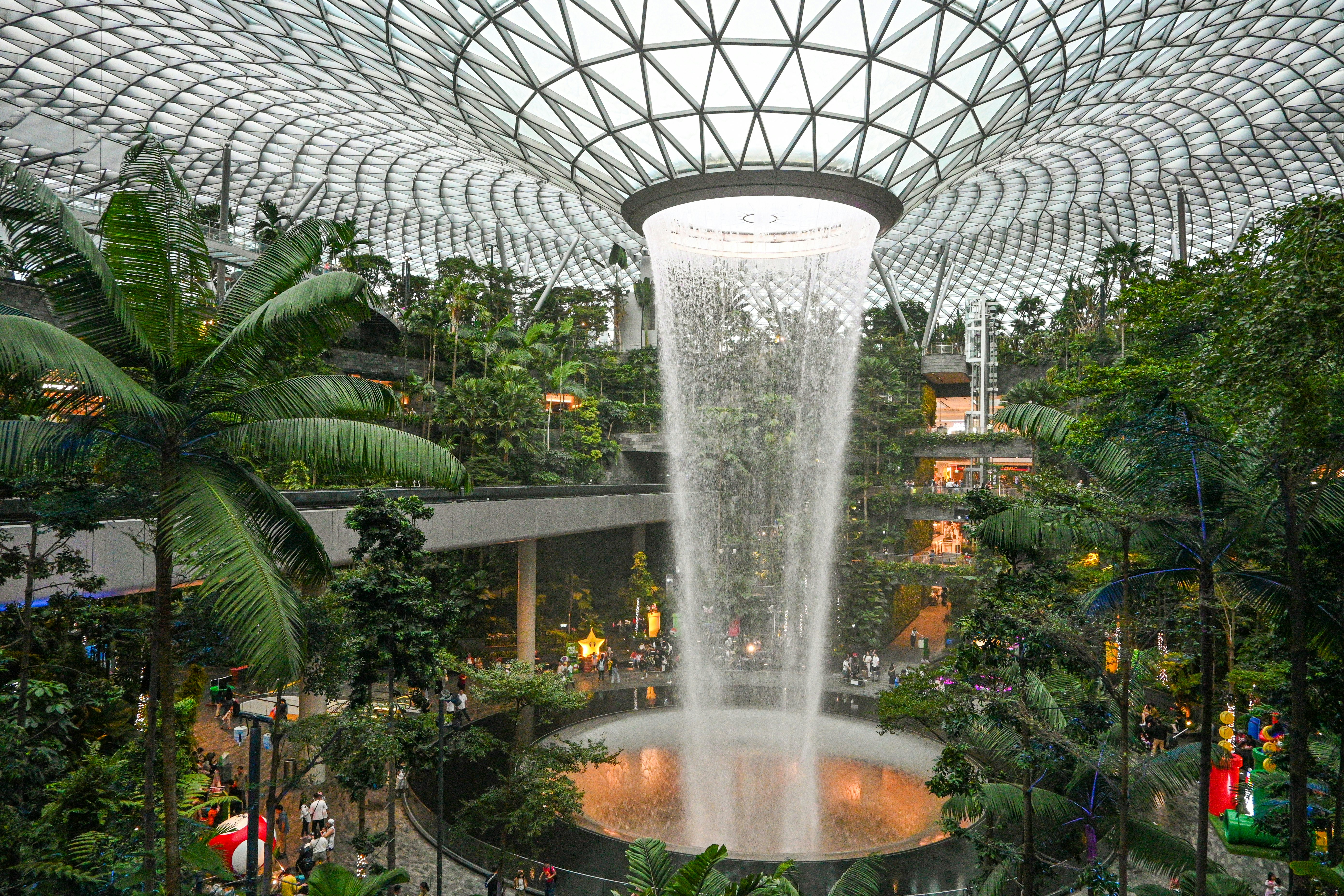 Cascading Glass Dome Oasis: Waterfall within a Lush Atrium