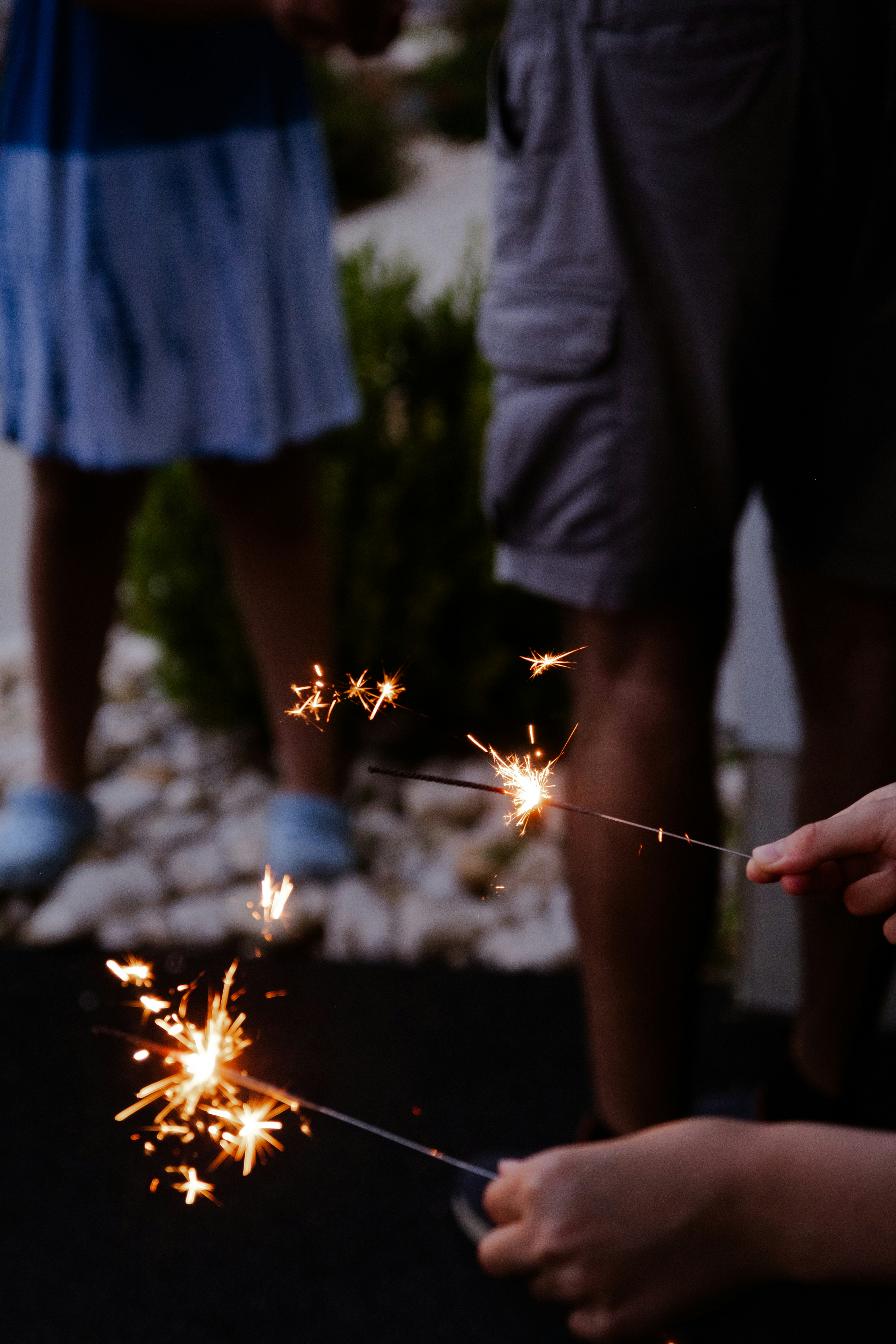 Sparks in the Night: Hands with Sparklers Against Shadowed Figures